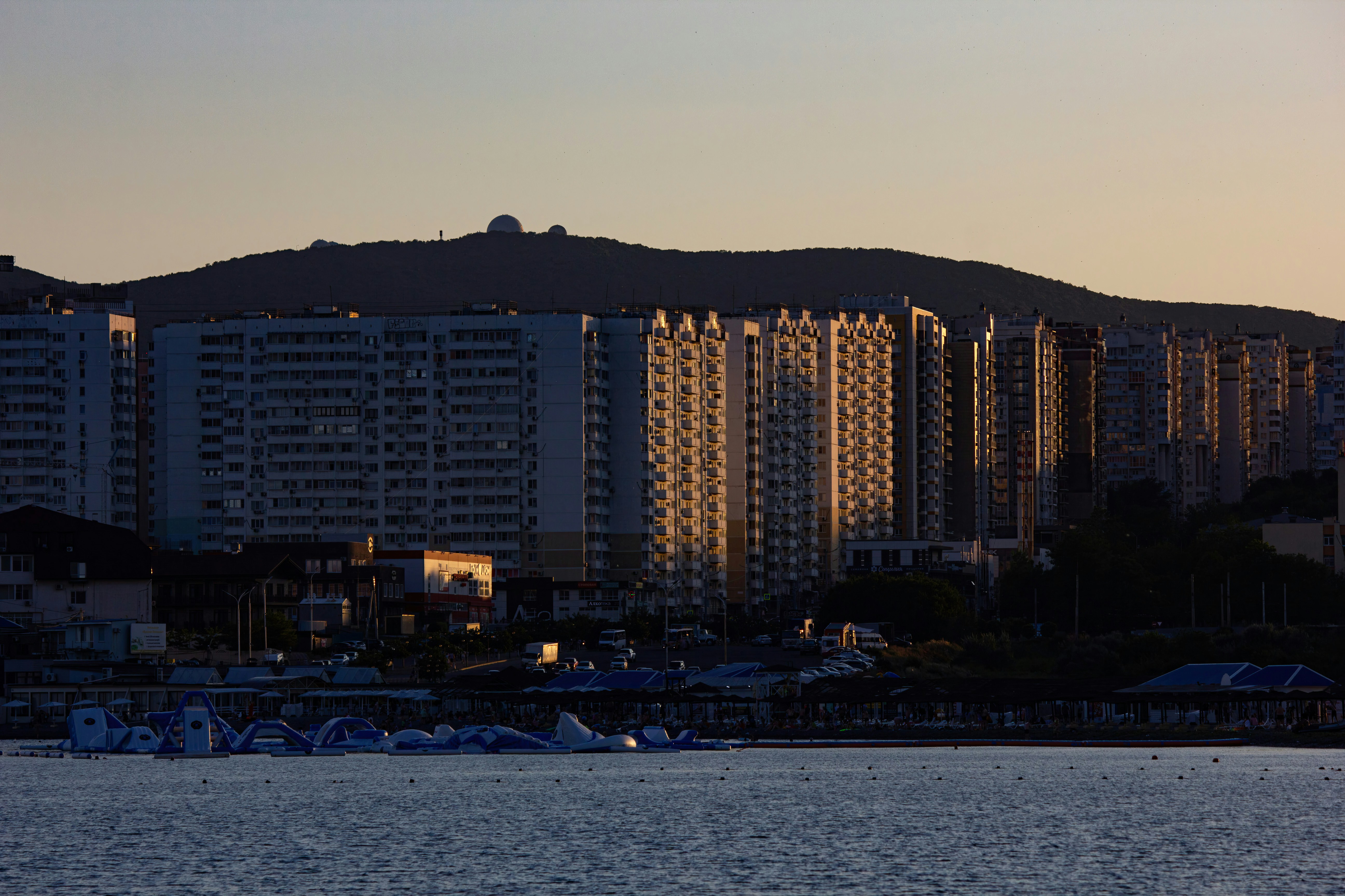 Coastal high-rise silhouette at golden hour with hillside beacon