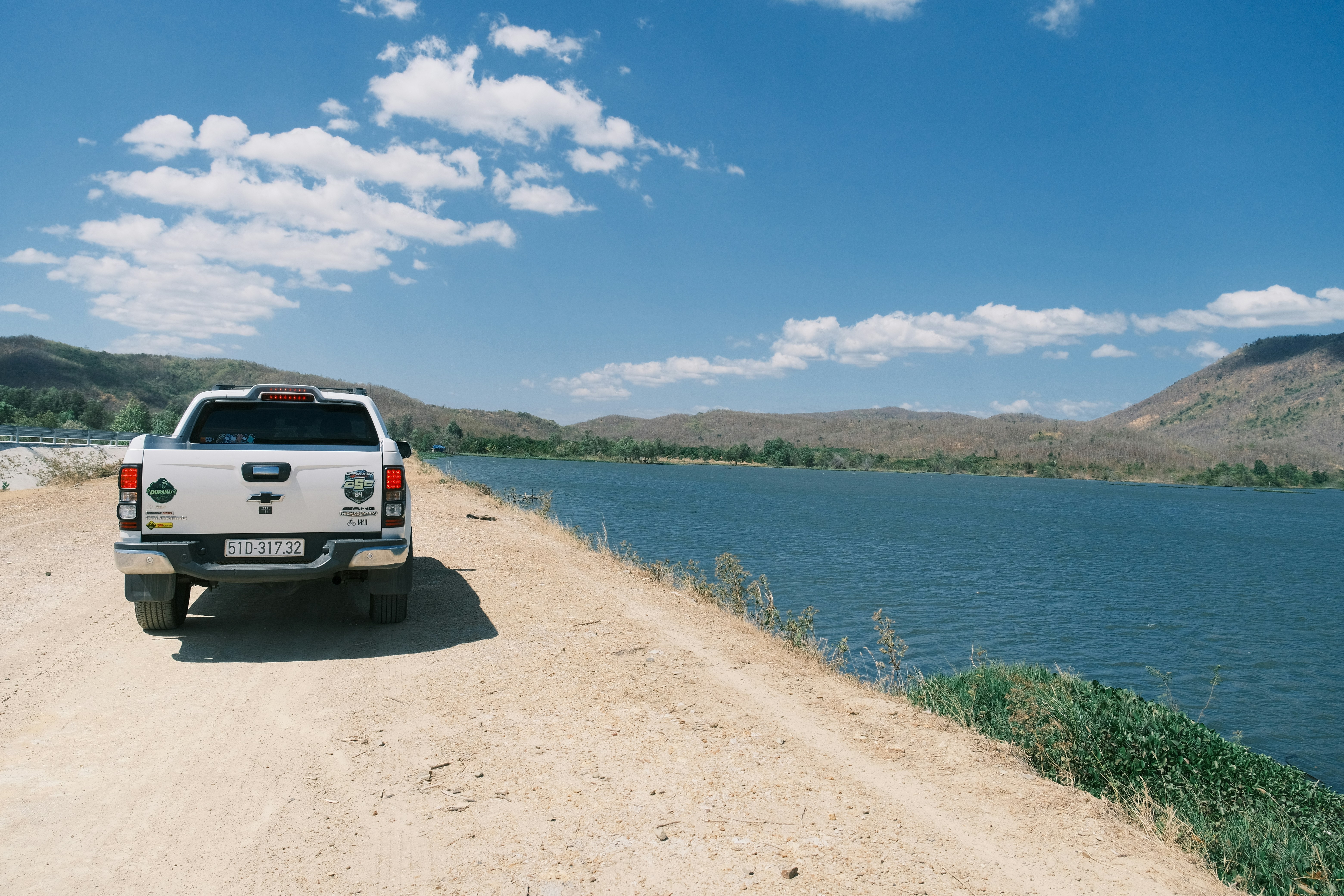 Dusty Riverside Road Trip: A Pickup Paused by the Lake