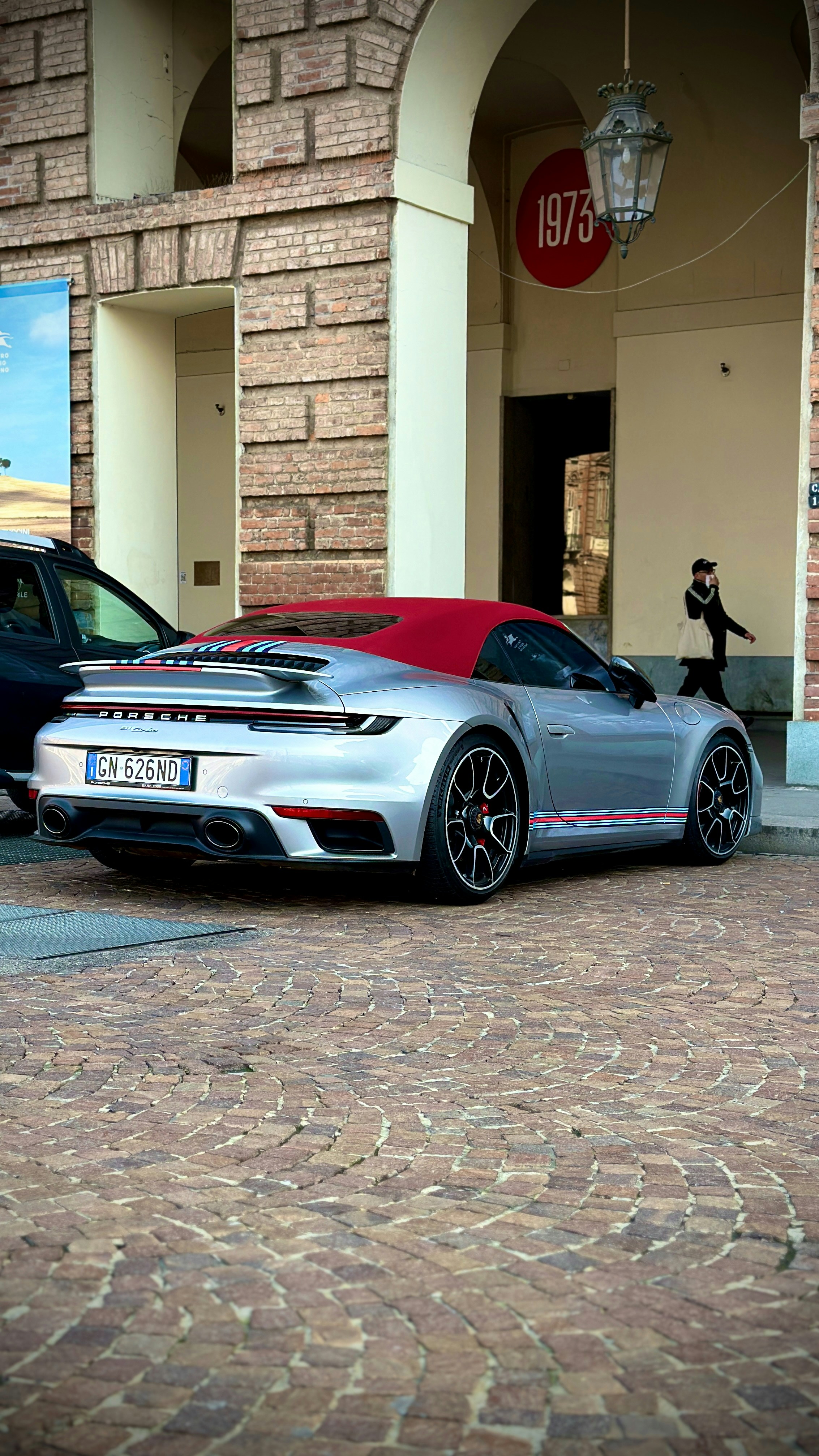 Crimson Roof, Silver Porsche 911: A Cobblestone Courtyard Rendezvous