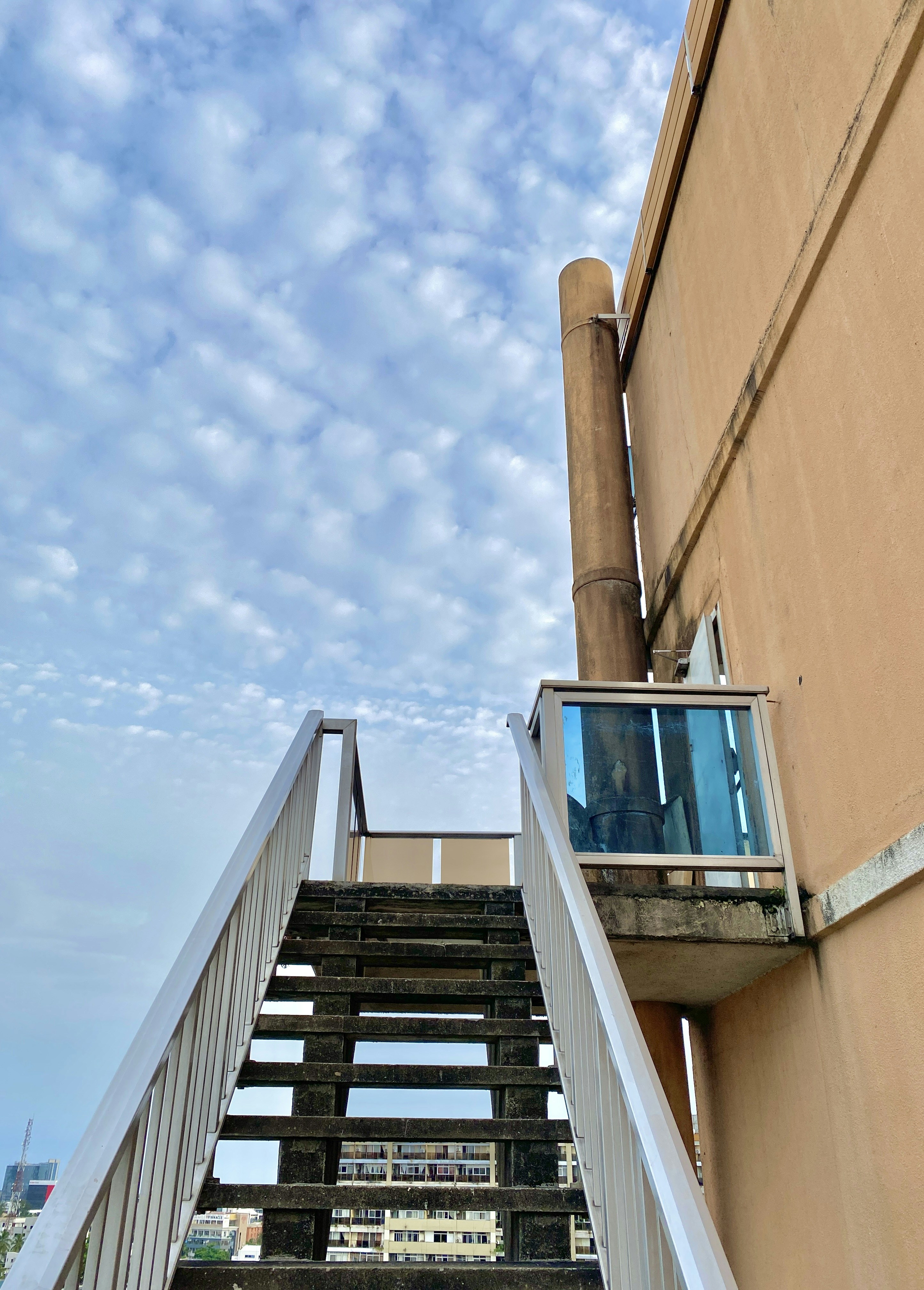 Stairway to the Sky: rooftop ascent under a quilt of clouds