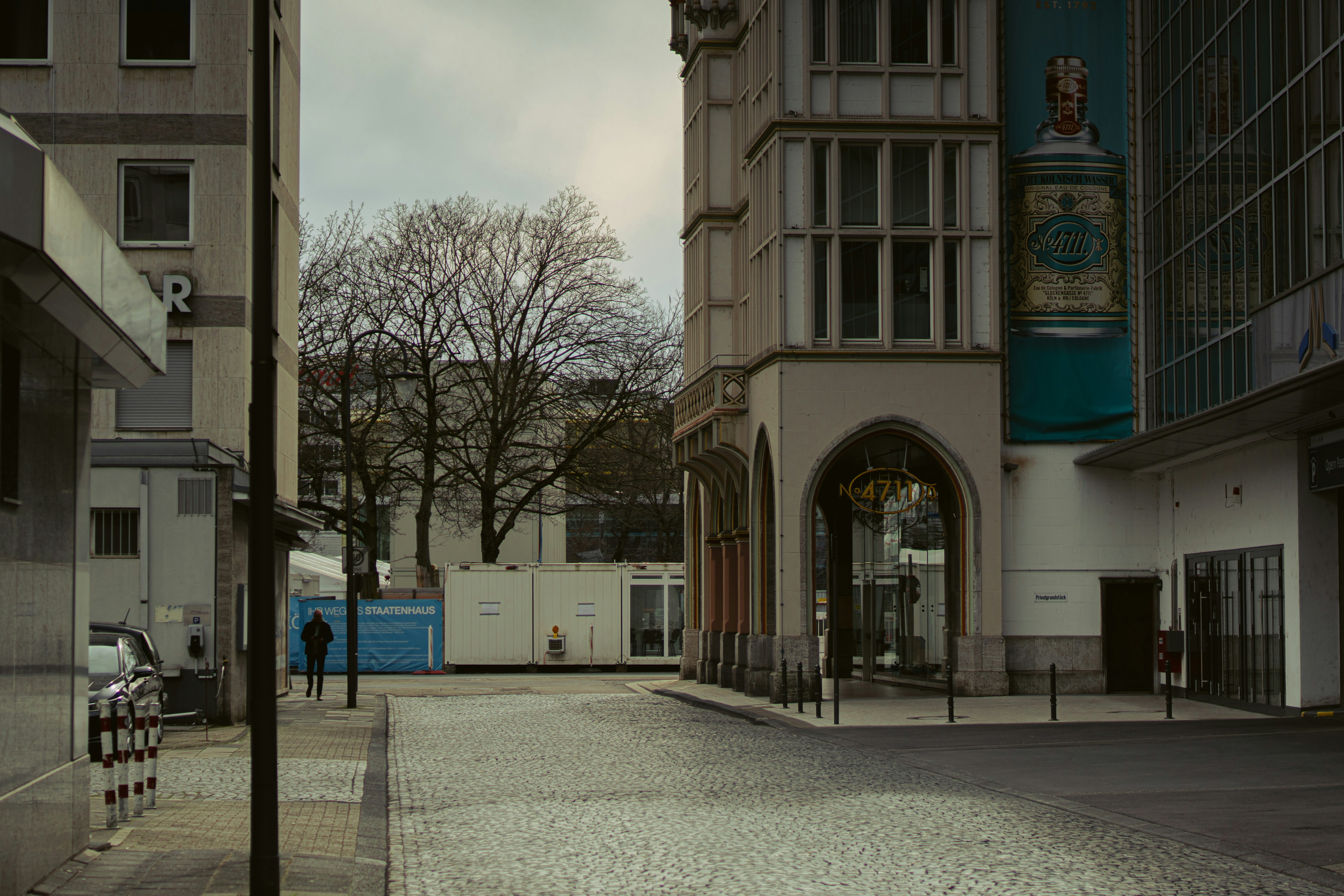 Distant Pedestrian Framed by Historic Facades Along a Cobblestone Street