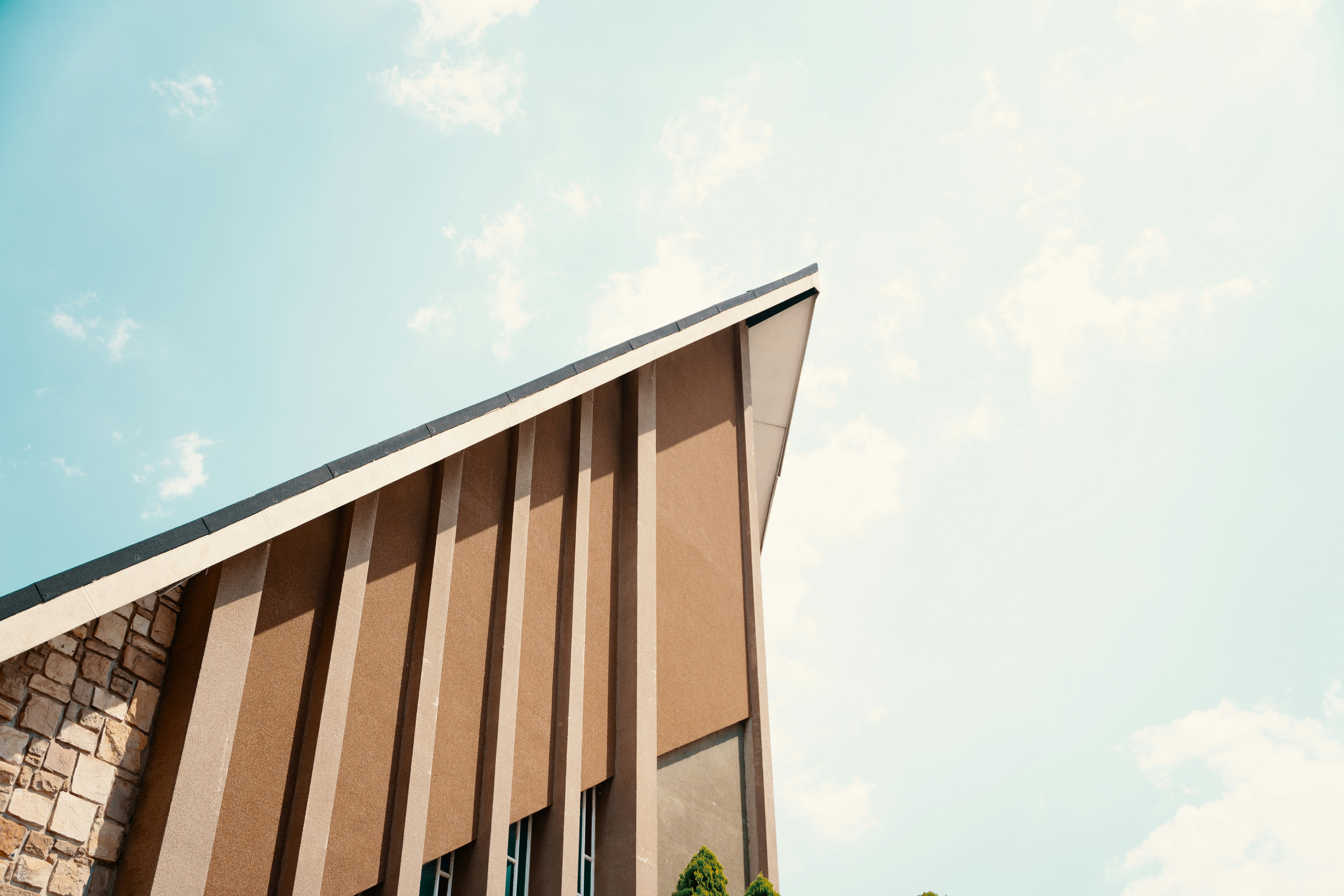 Modern building facade with clock, featuring vertical lines and stone accents under a bright sky.