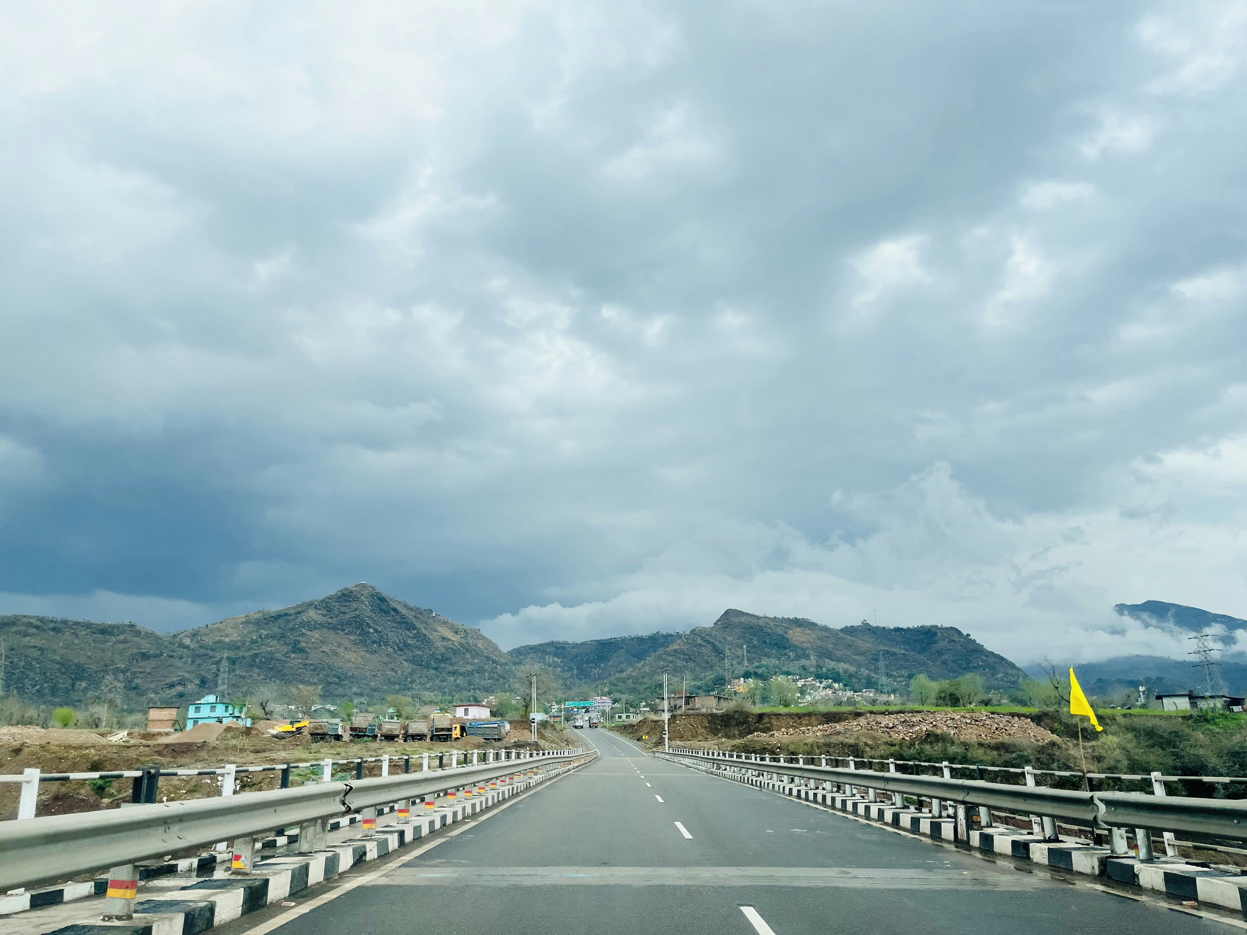 Vanishing Highway: Bridge Toward Distant Mountains Under Cloudy Skies