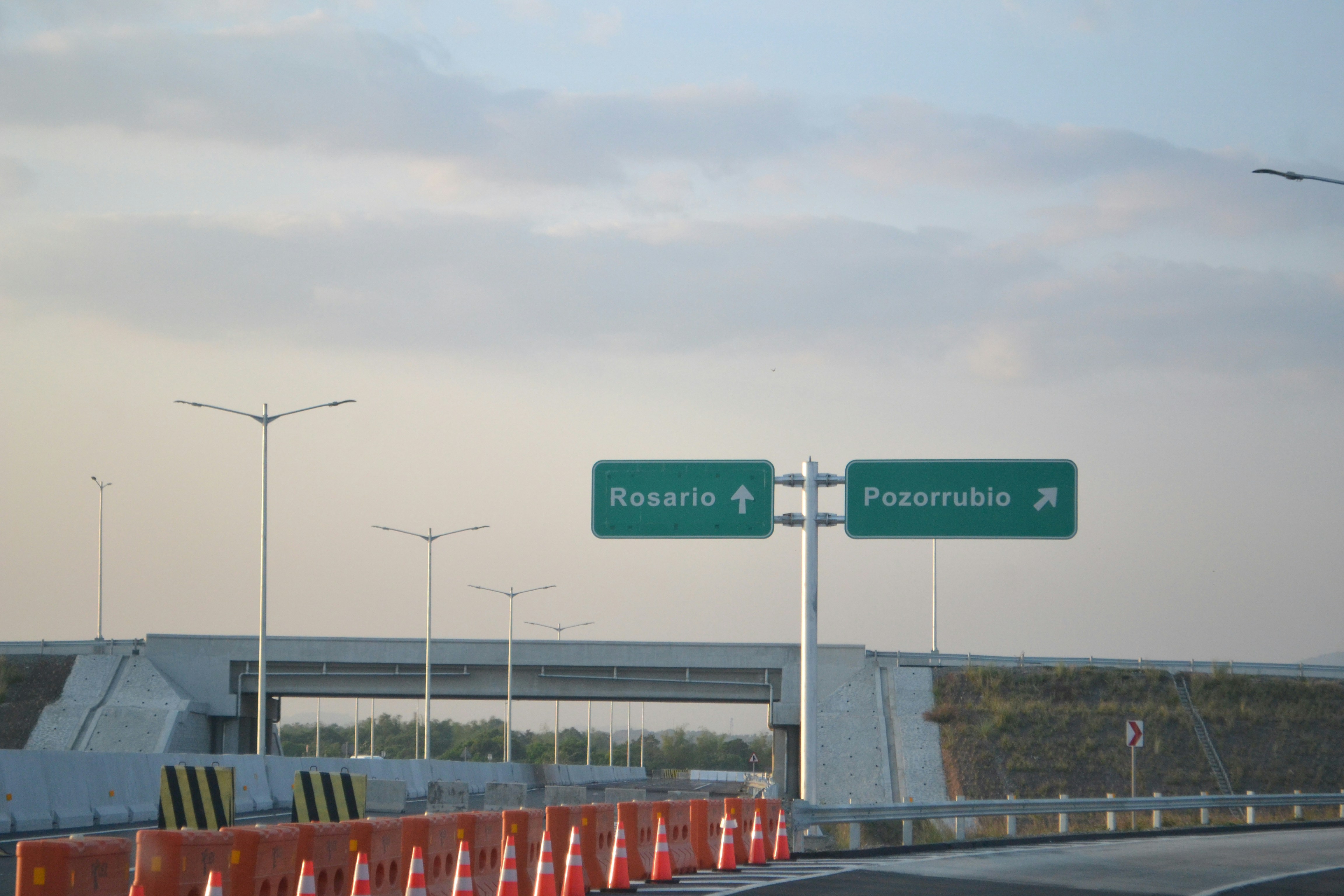 Highway with directional signs under a pastel sky at dawn.