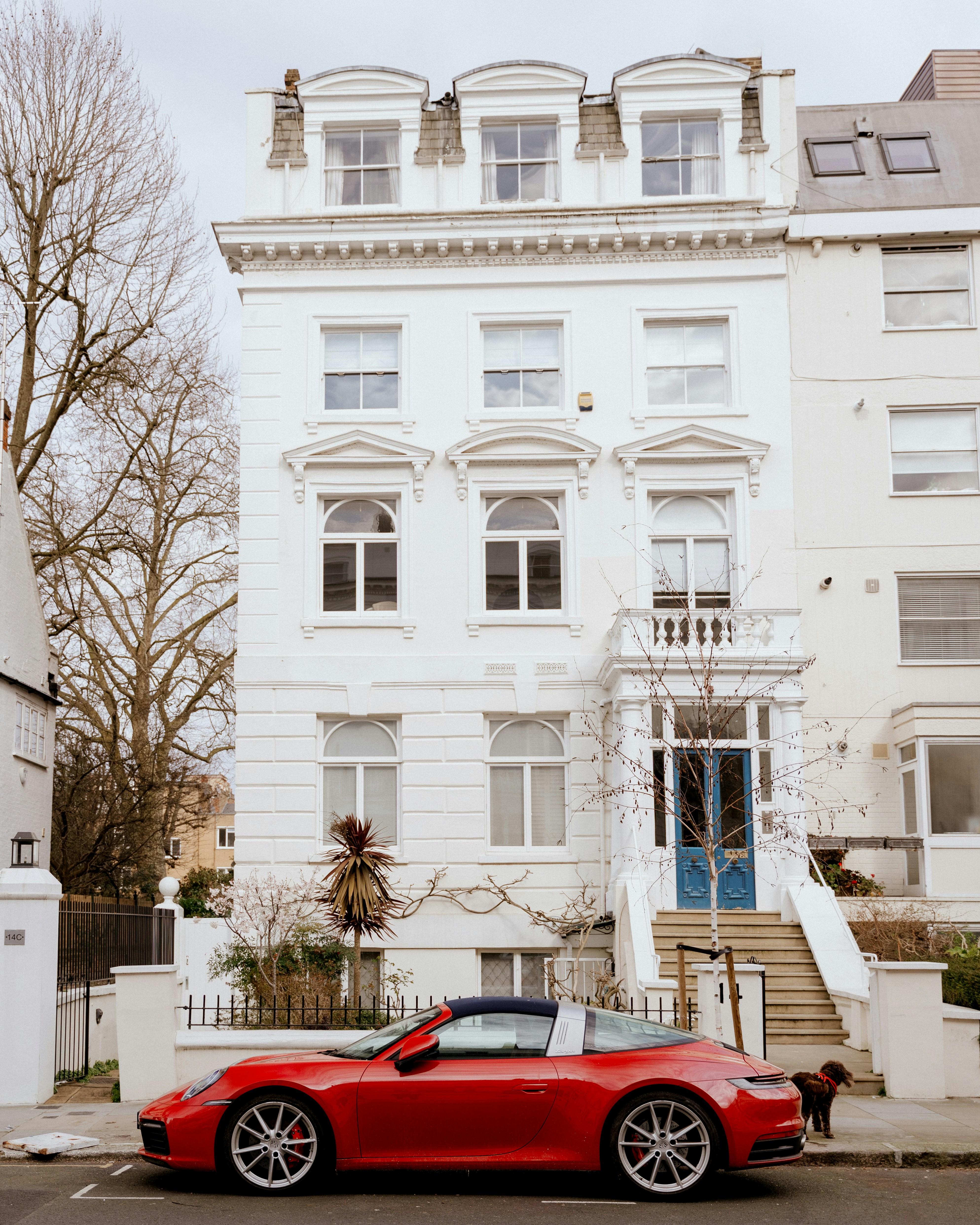 A red sports car parked in front of a white building photo – Free ...