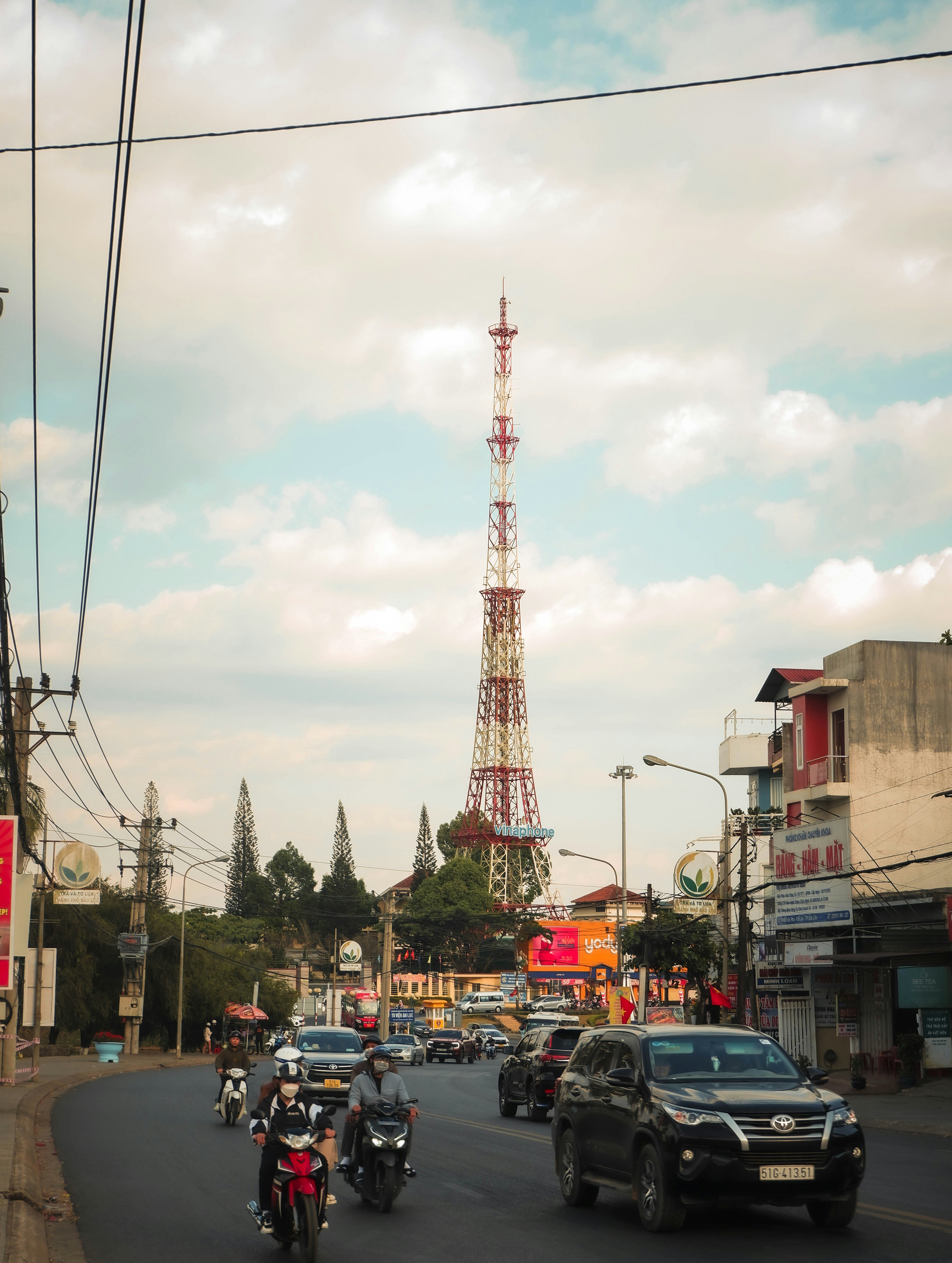 Lattice Tower Over a Bustling Street: Red-and-White Signal Amid a Sunny Townscape