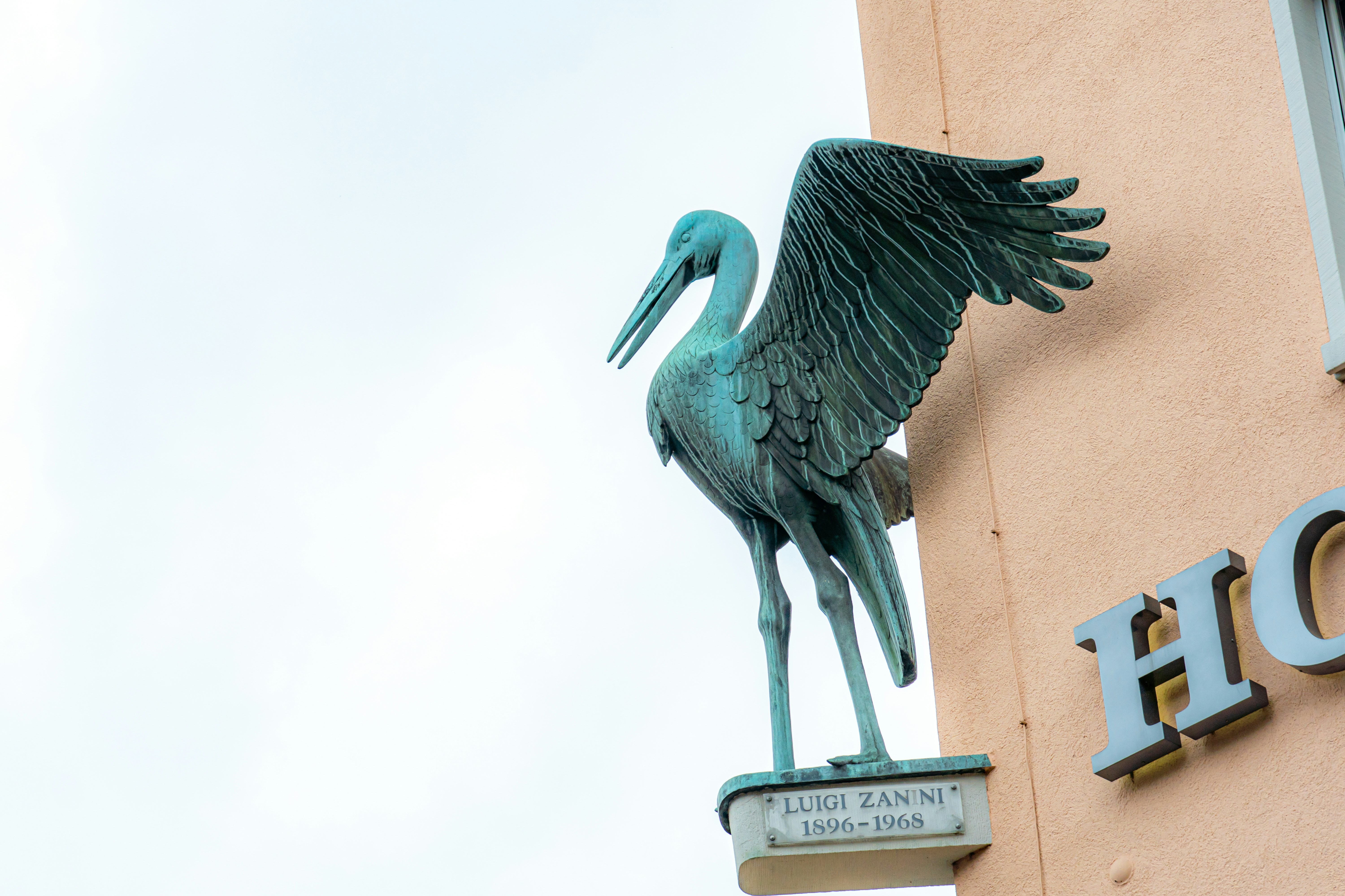 Heron Statue on the Corner: A bronze bird perched beside a building
