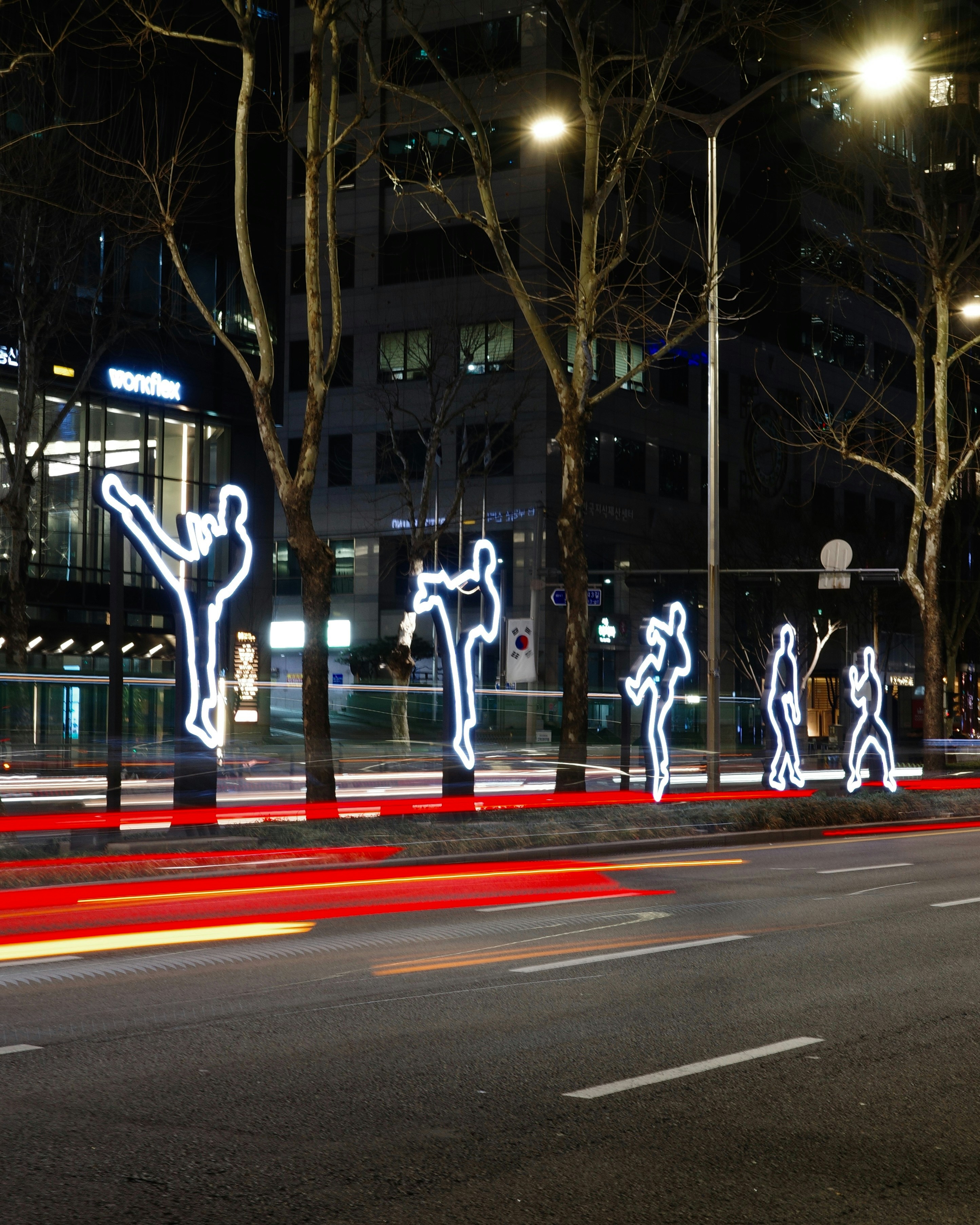 Neon-Outlined Figures Parade Along a Night Street