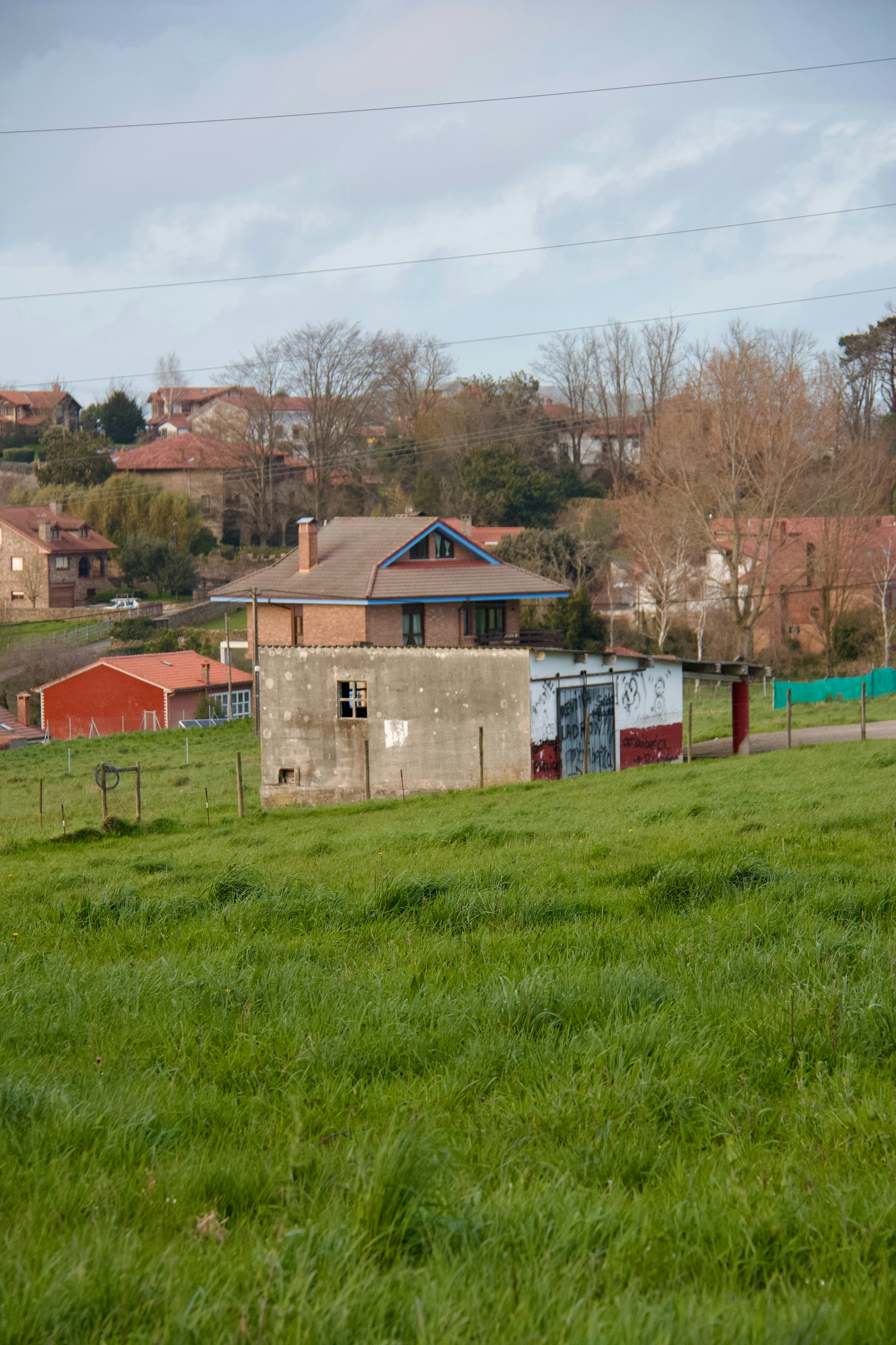 Blue Roof on the Hill: A Quiet Field Scene with a Weathered Shed and Distant Homes