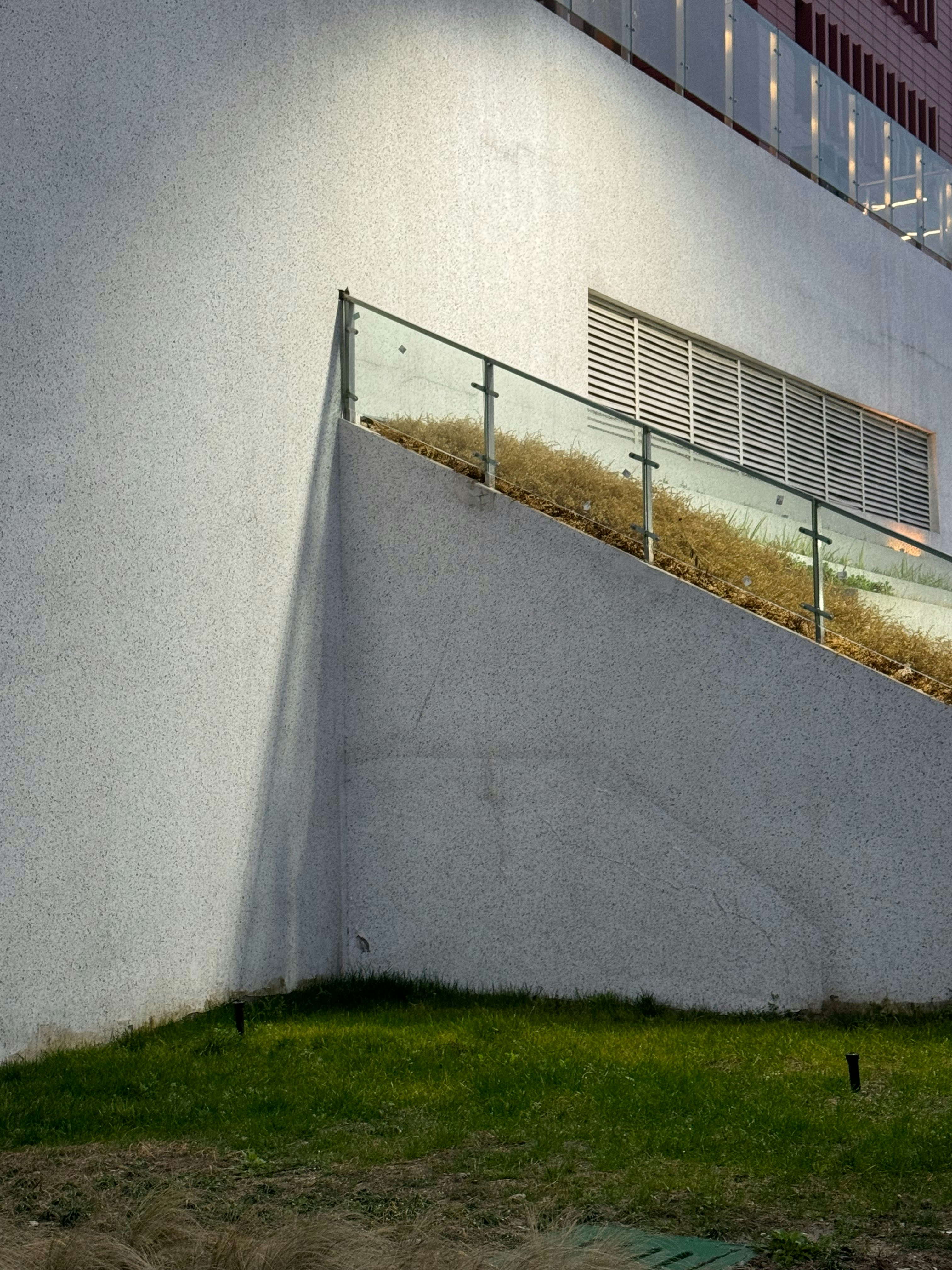 Diagonal Light: Glass Railing Over a Clean Concrete Facade