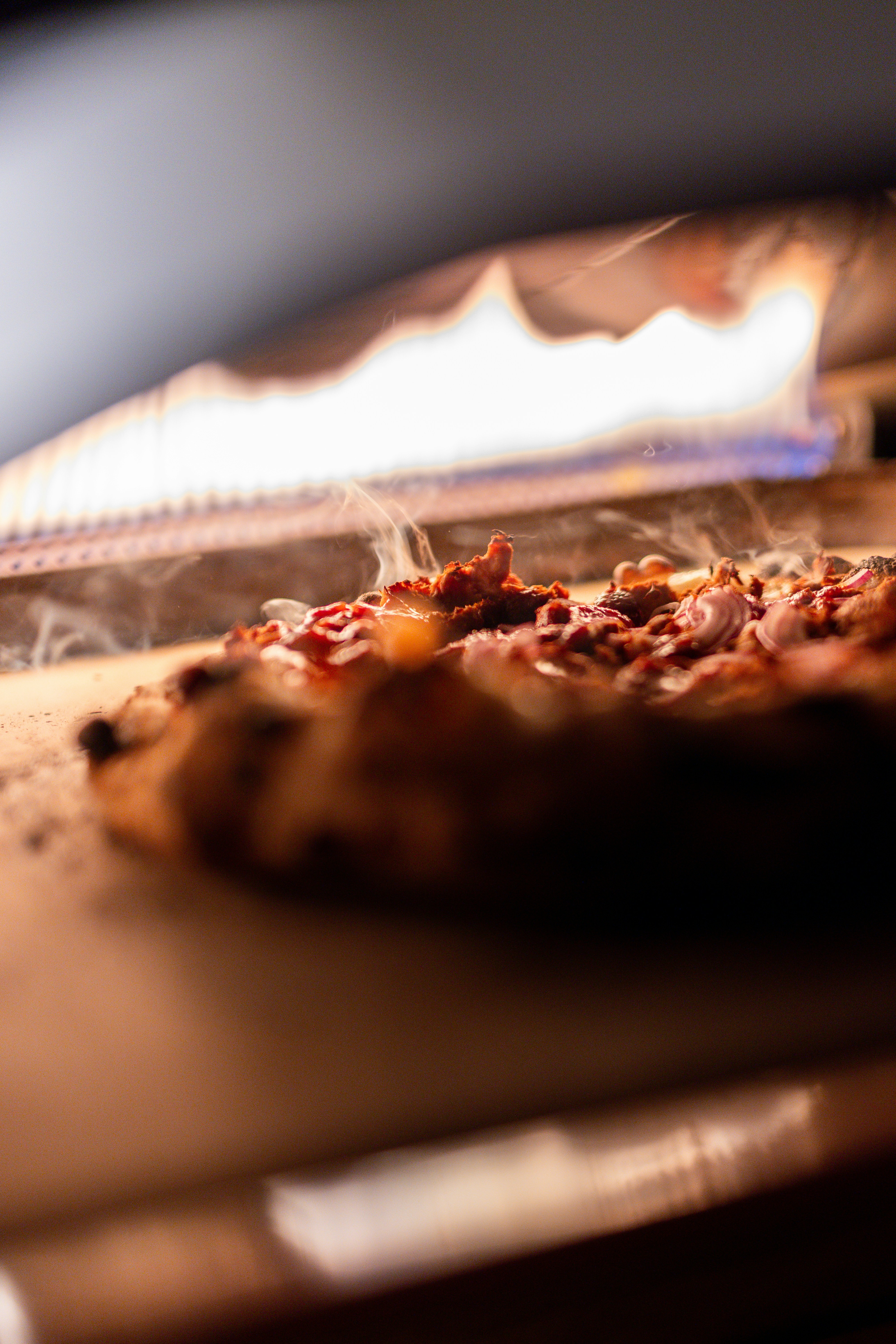 Blazing Oven Spotlight on Charred Pizza Beneath a Dancing Flame