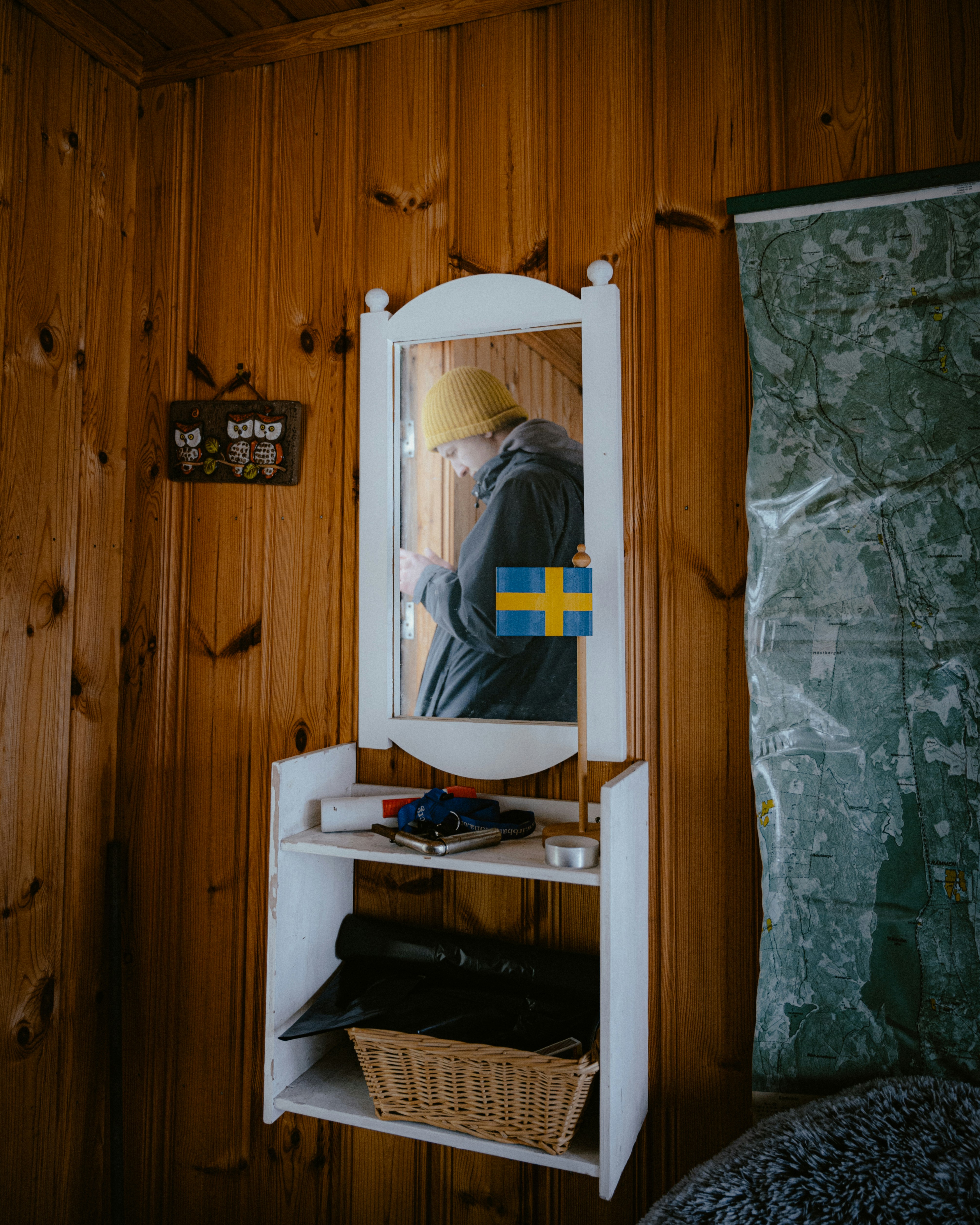 Quiet Cabin Reflection: Beanie, Mirror, and a Swedish Flag