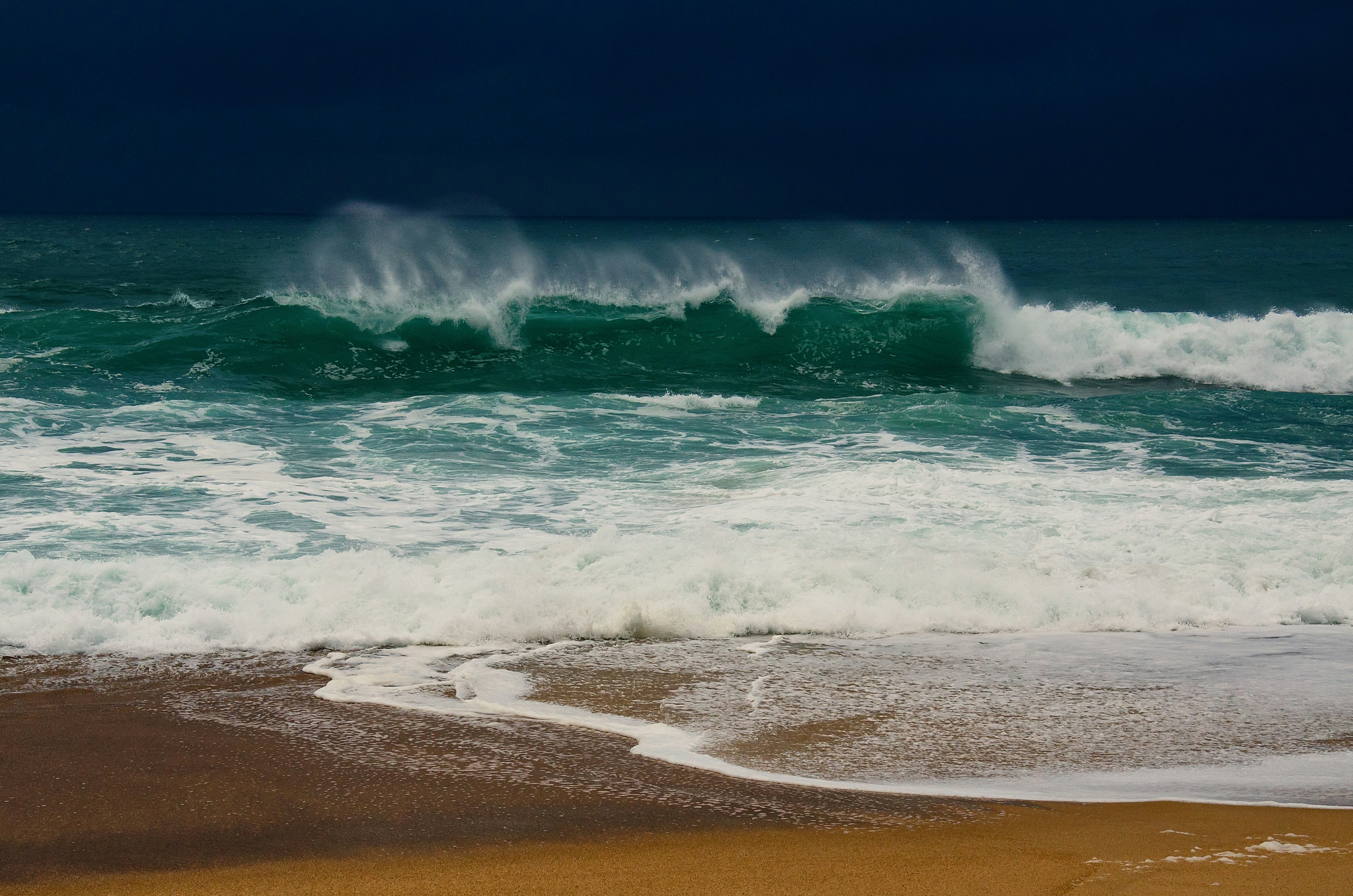 Una gran ola rompiendo en la orilla de una playa foto – Imagen de ...