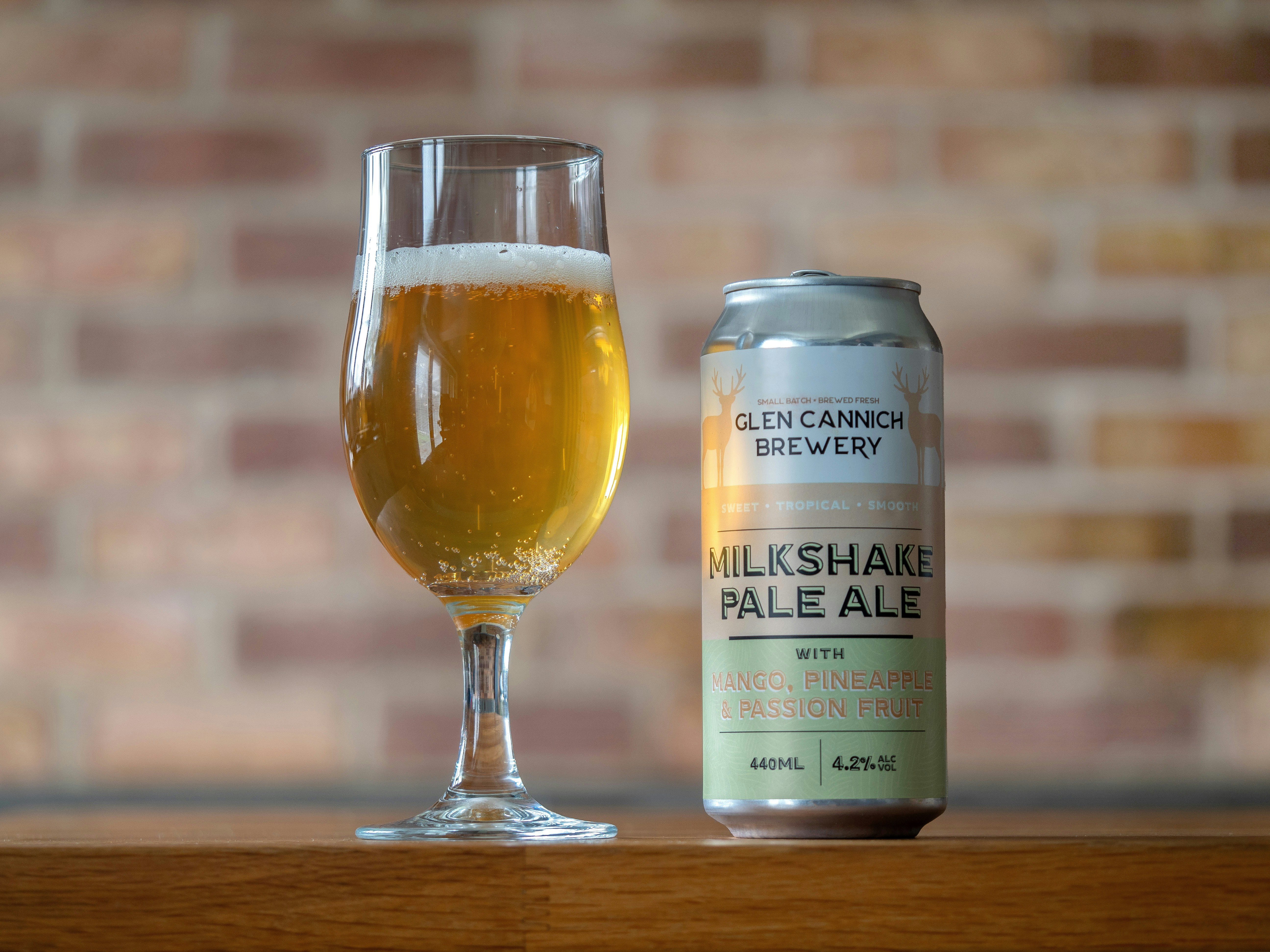 A glass of beer next to a can of milkshake pale ale photo – Free ...