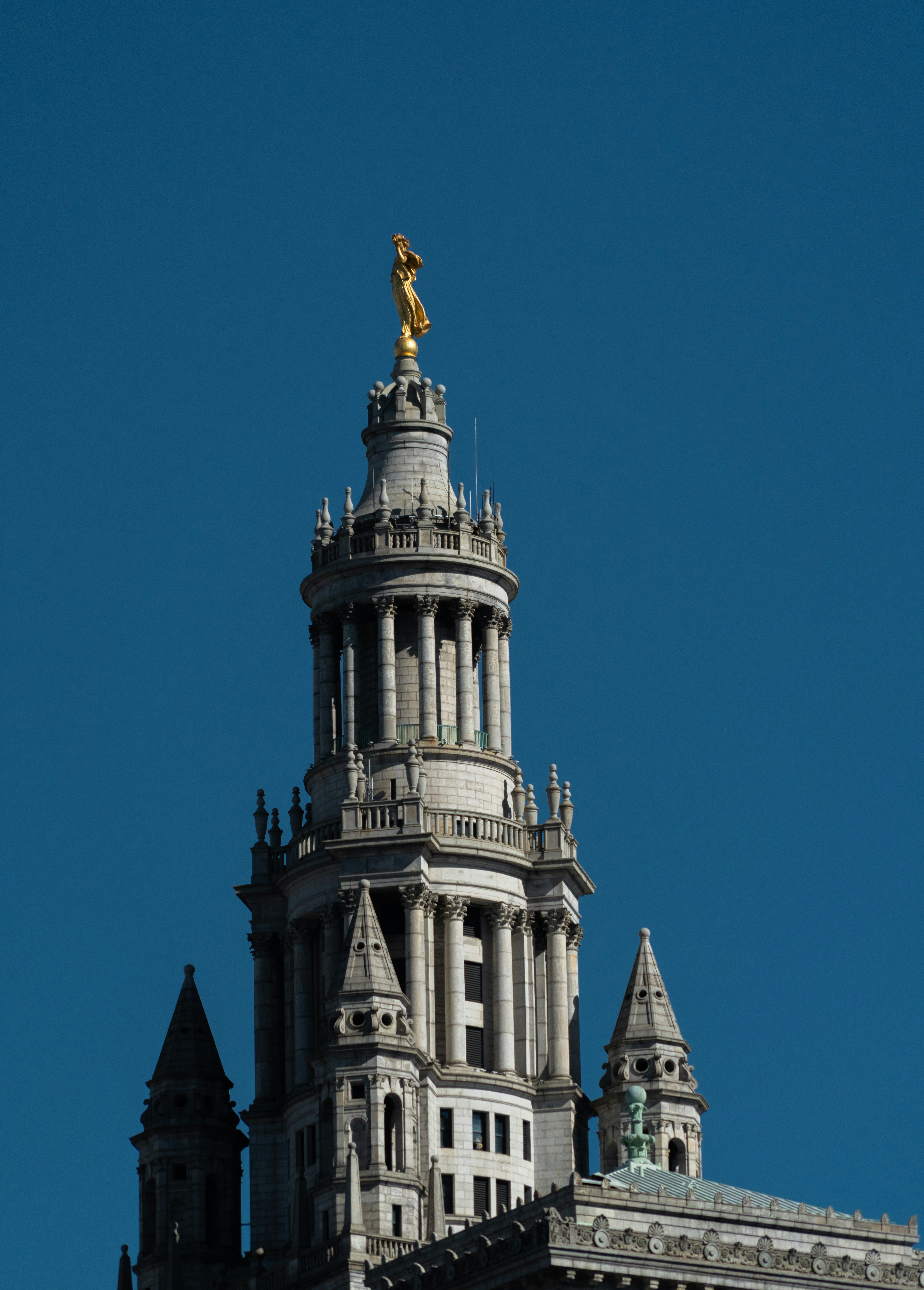 Golden Statue Crowned Tower Piercing a Cerulean Sky