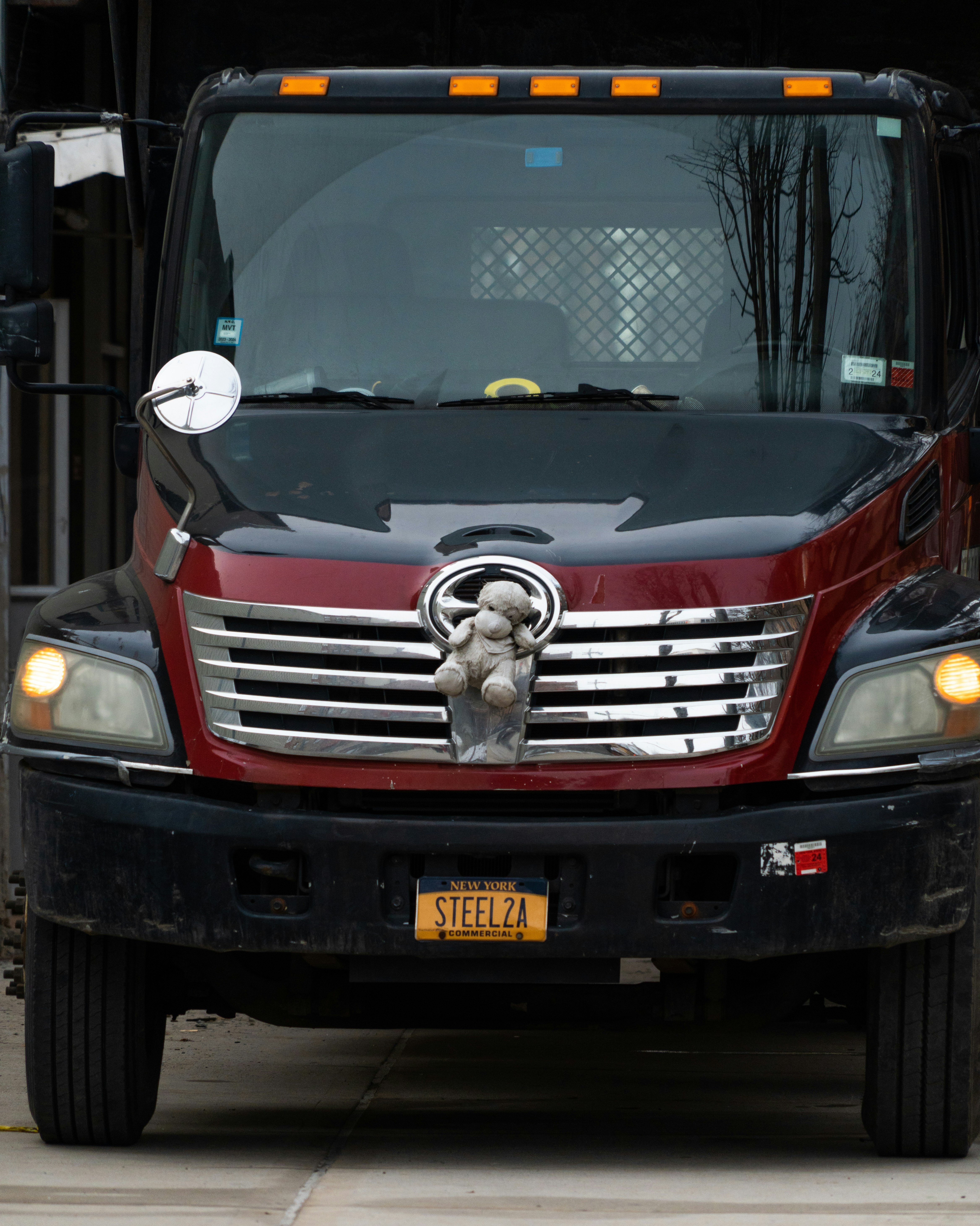 Grille Guardian: Plush Toy Anchors a Red Work Truck
