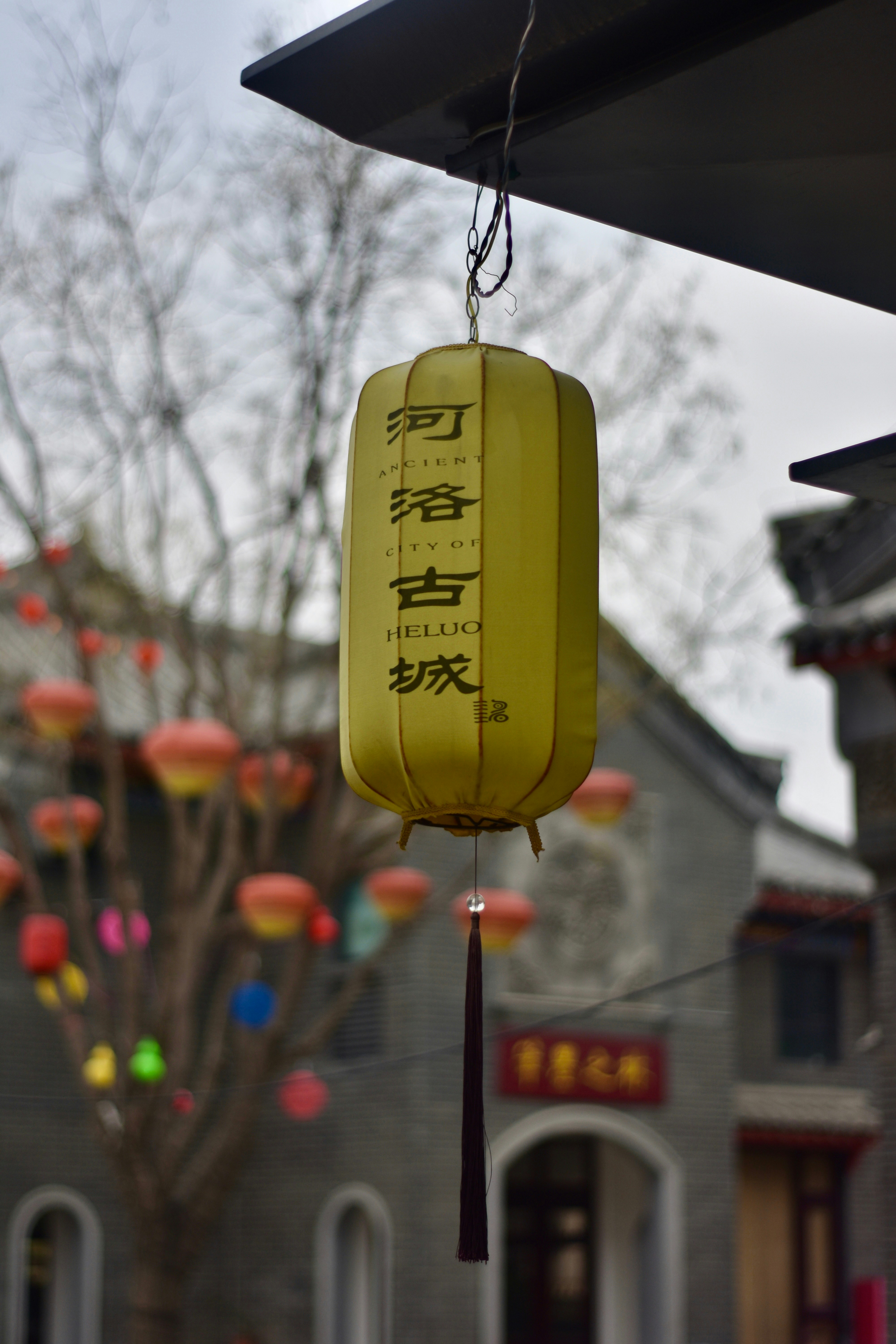 Hanging Yellow Lantern Framed by a Street of Colorful Lanterns