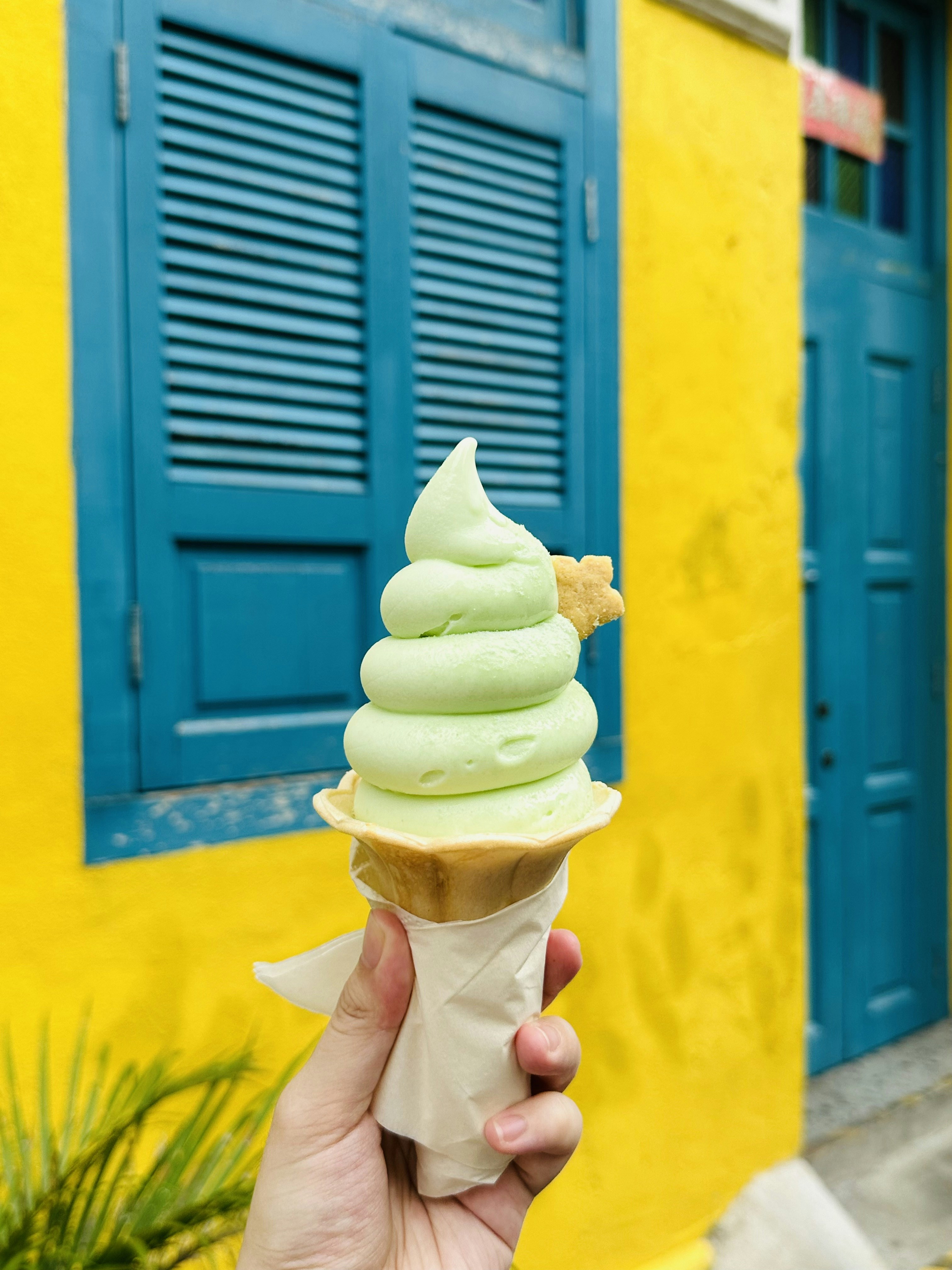Lime Swirl Cone Framed by Bold Blue Doors on a Sunlit Yellow Wall