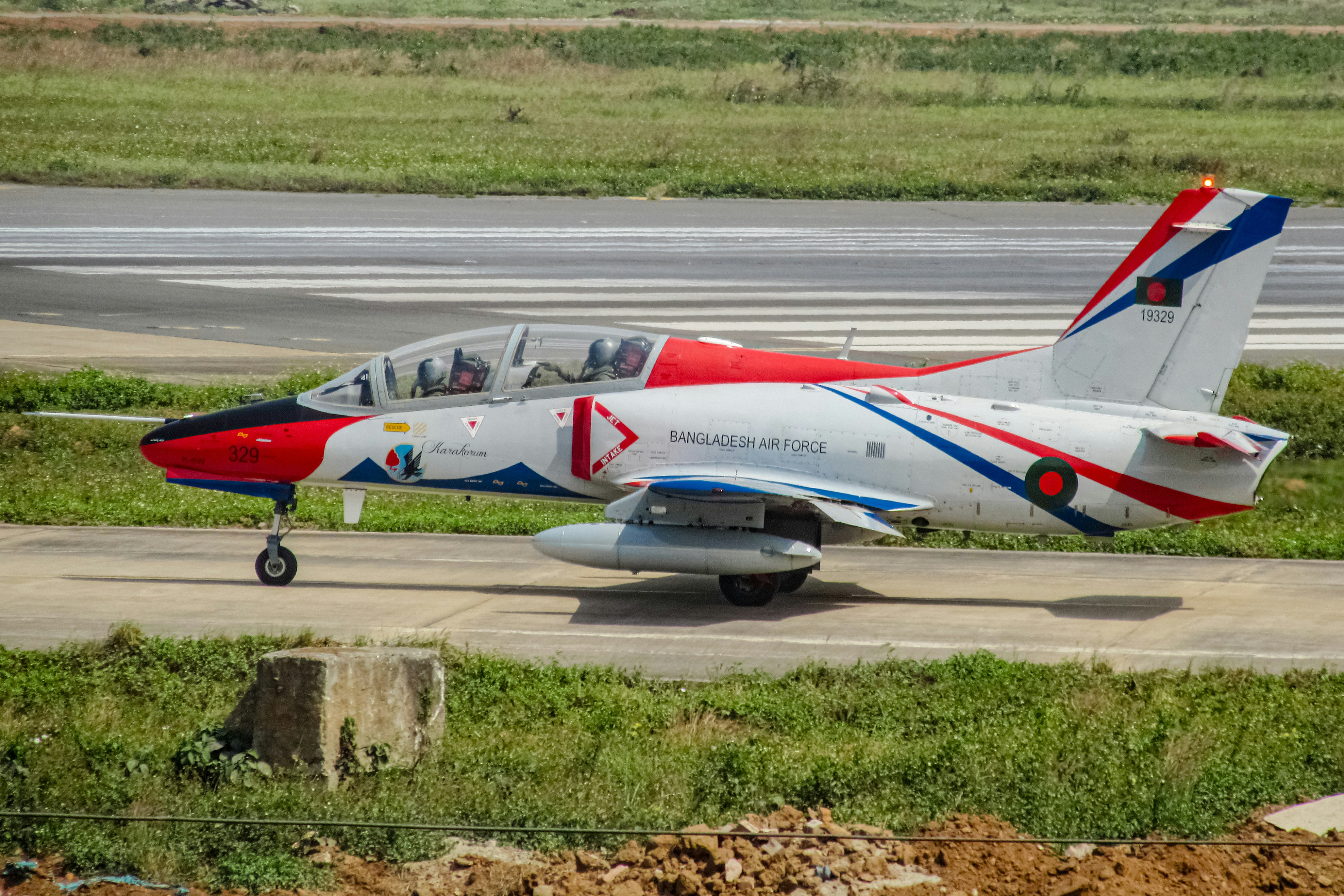 A red, white and blue fighter jet sitting on top of an airport tarmac ...