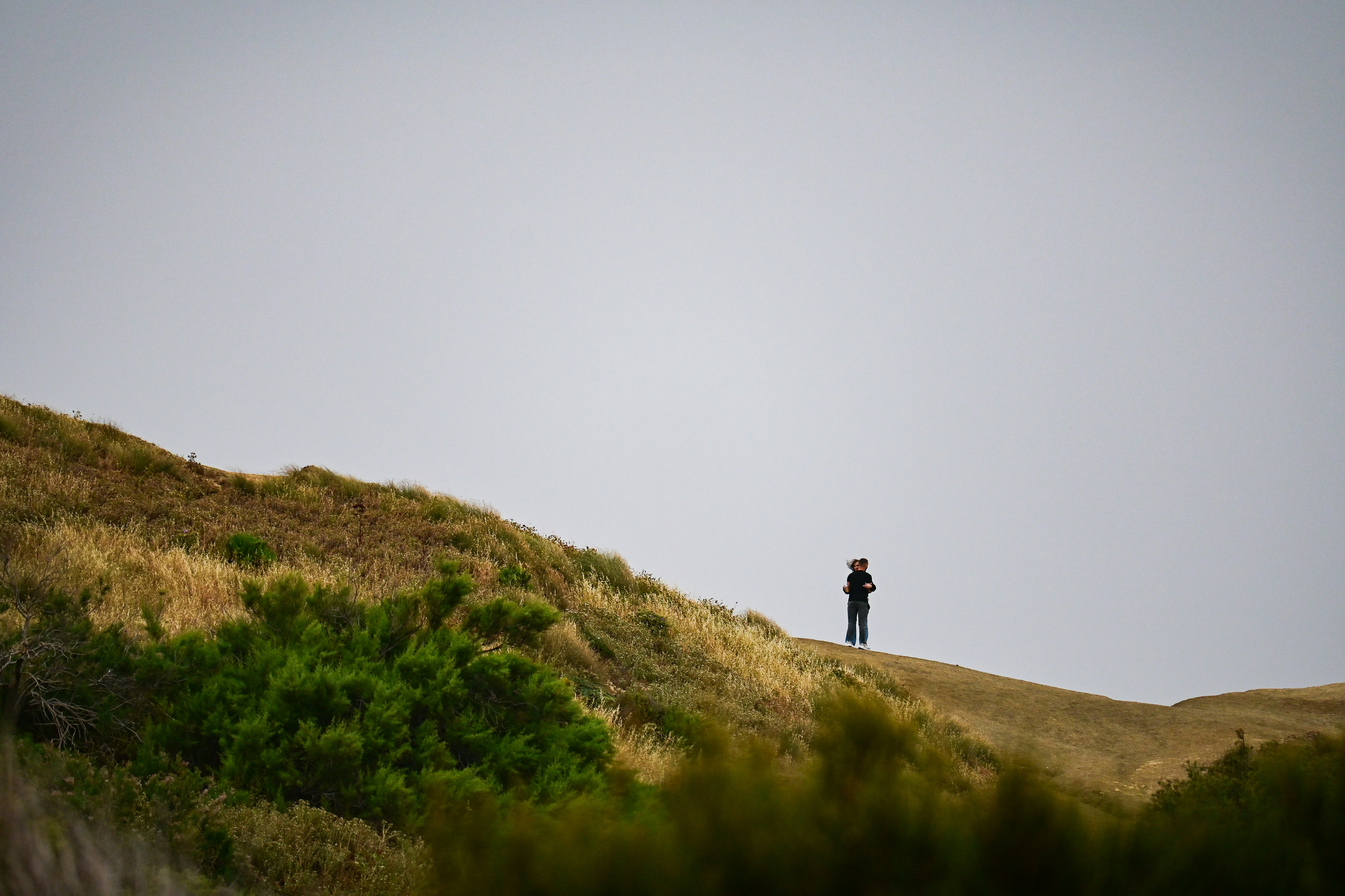 Dancing on Hills: A landscape shot on a cloudy day, marked by a dancing couple in the distance, taken in Malta.