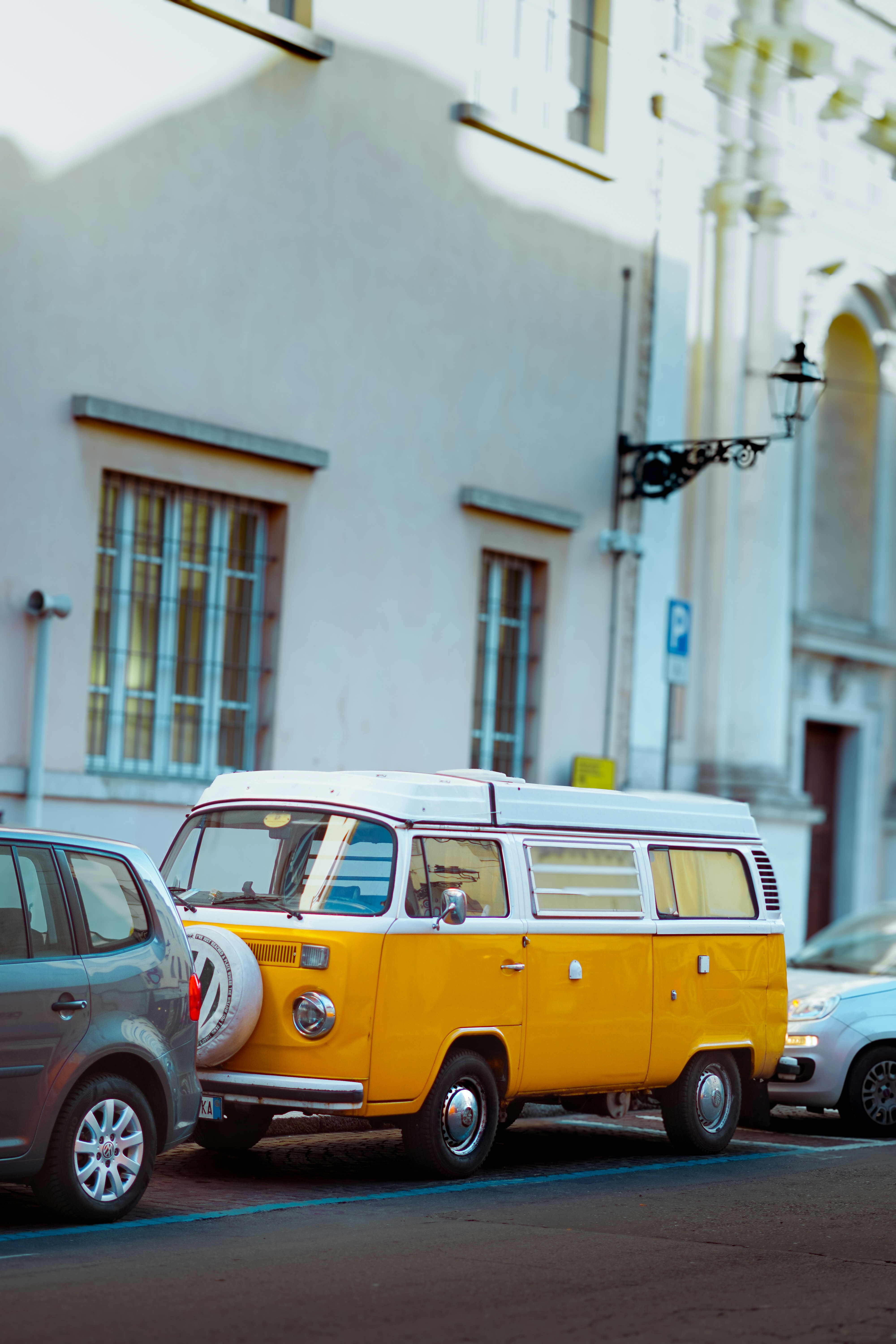 A yellow and white van parked next to a car photo – Free Car Image on ...