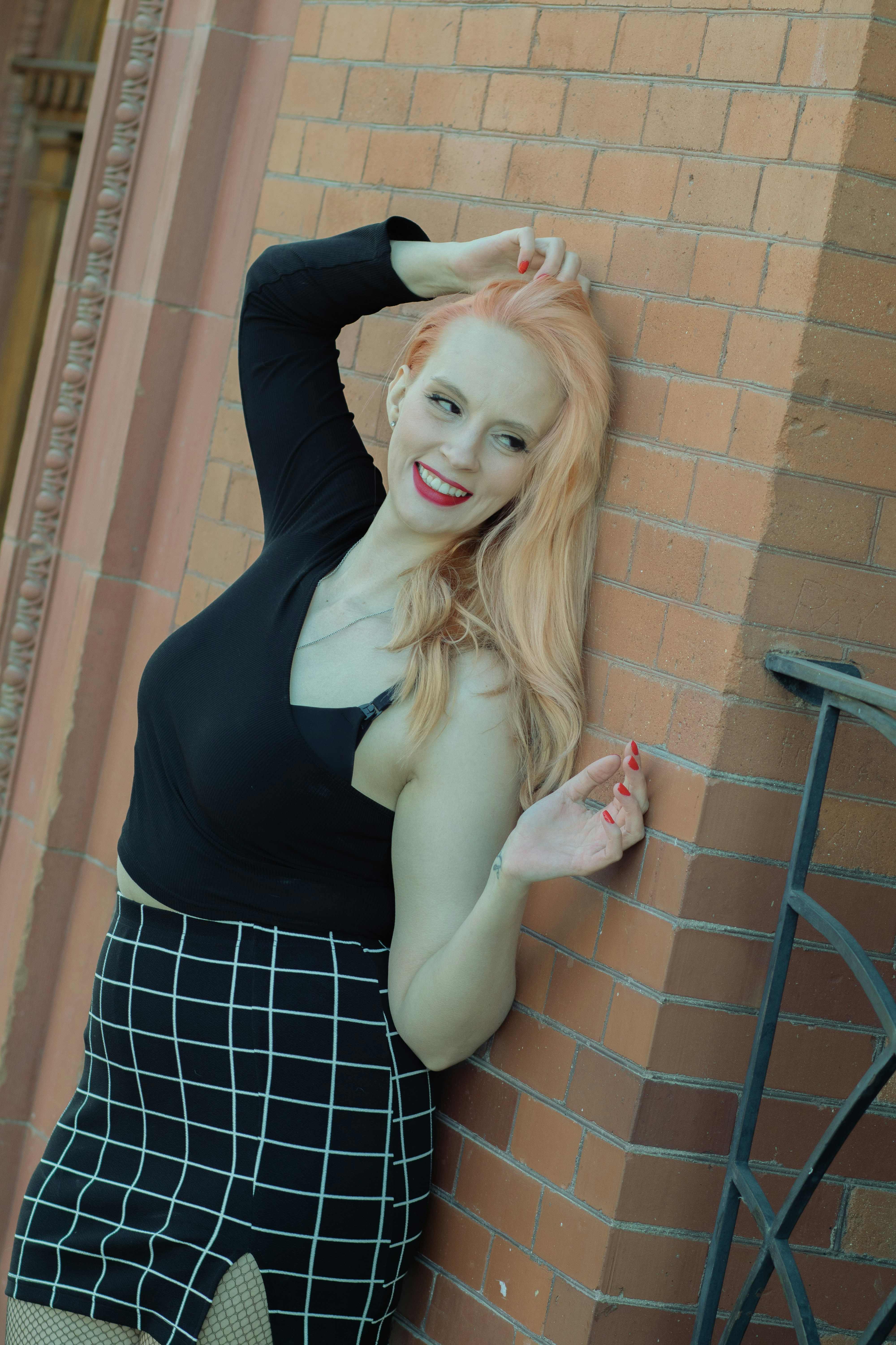 A woman leaning up against a brick wall photo – Free Photography Image ...