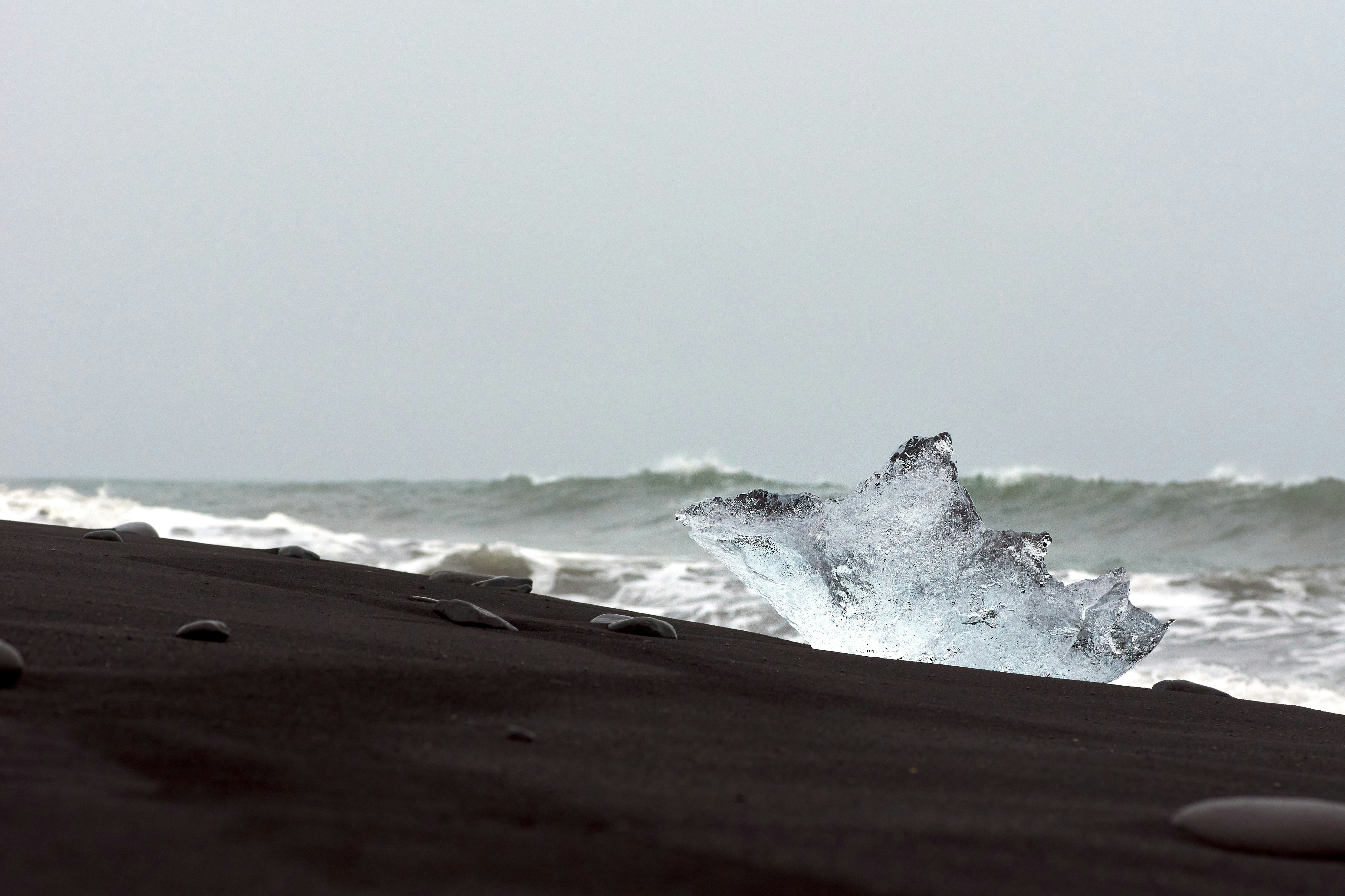 An icey piece of ice on a black sand beach photo – Free Water Image on ...
