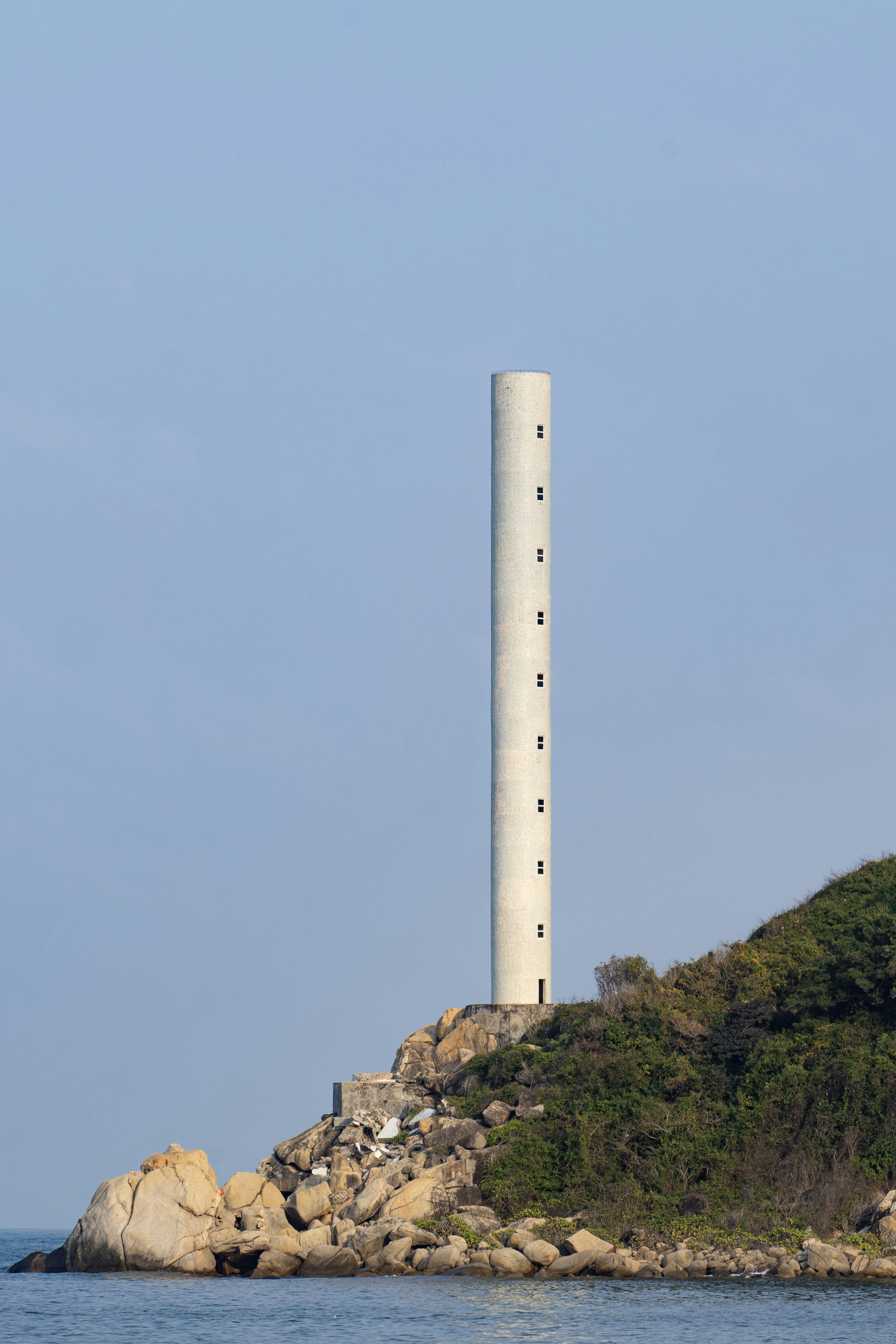 Sentinel on the Shore: A lone cylindrical beacon crowns a rocky promontory