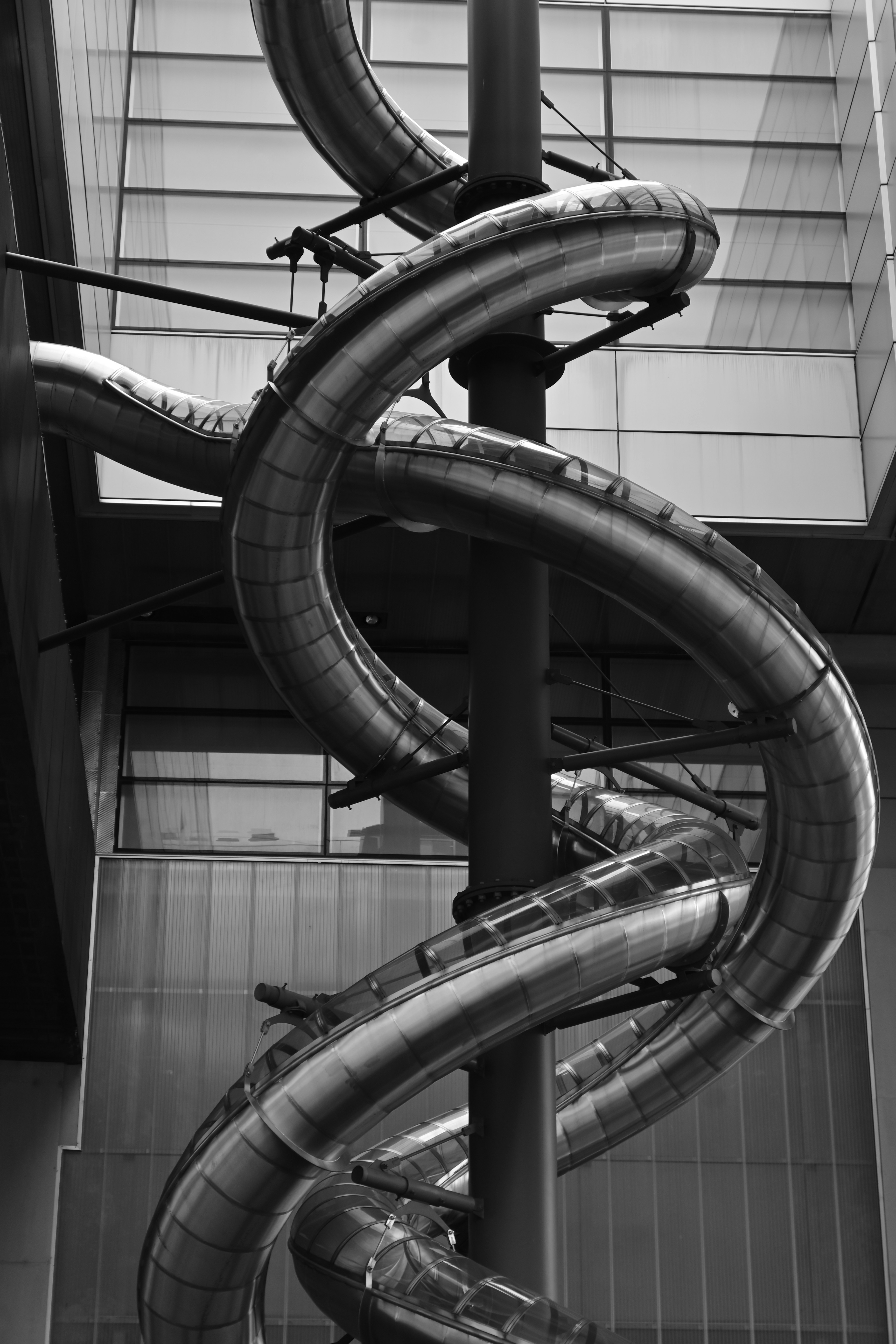 Coiled Metal Ribbon: A Vertical Gyre Through Glass and Steel