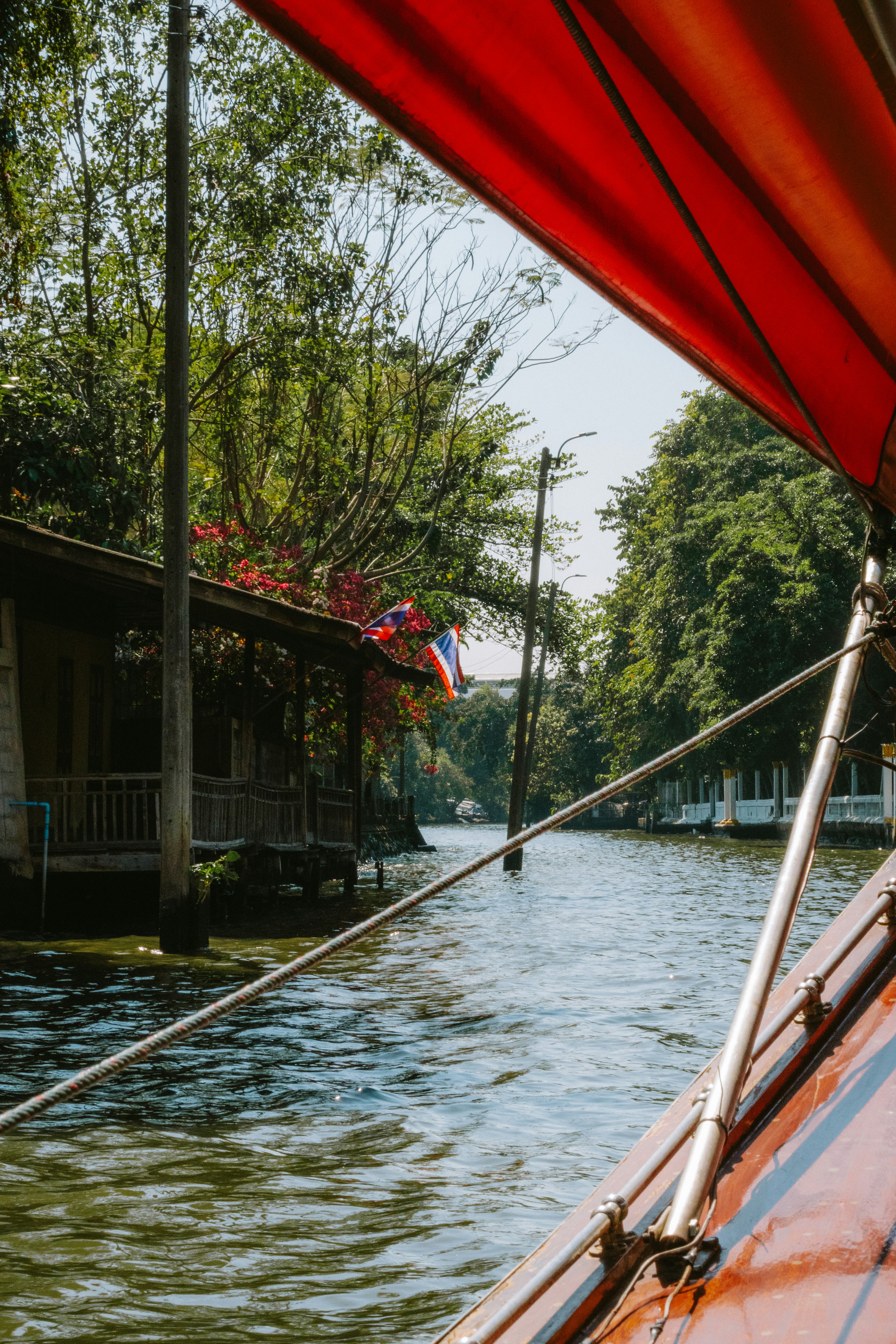 Flag-Bordered Riverside: A Red-Canopy View Down a Tranquil Canal