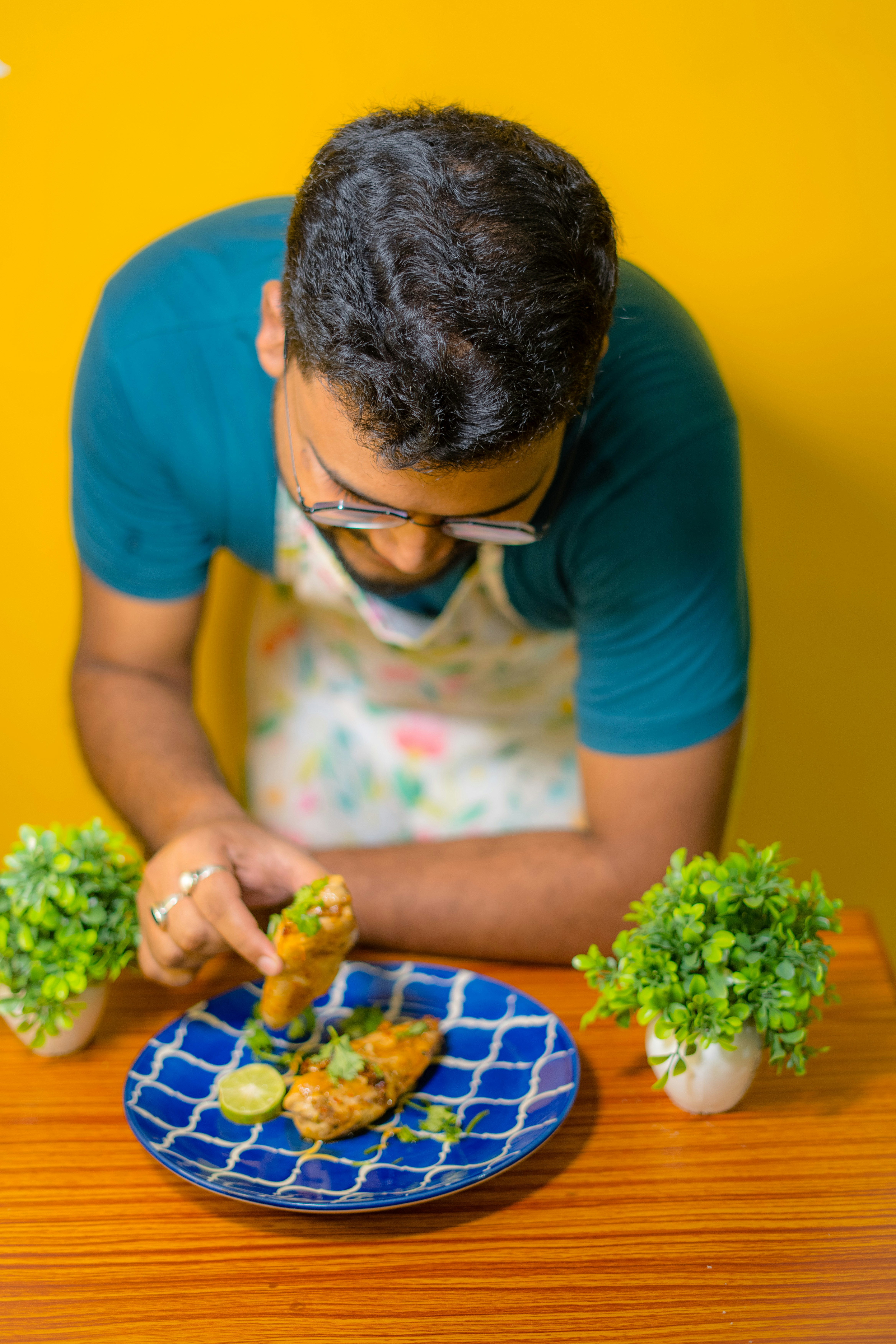 A man in glasses is eating food on a blue plate photo – Free Education ...