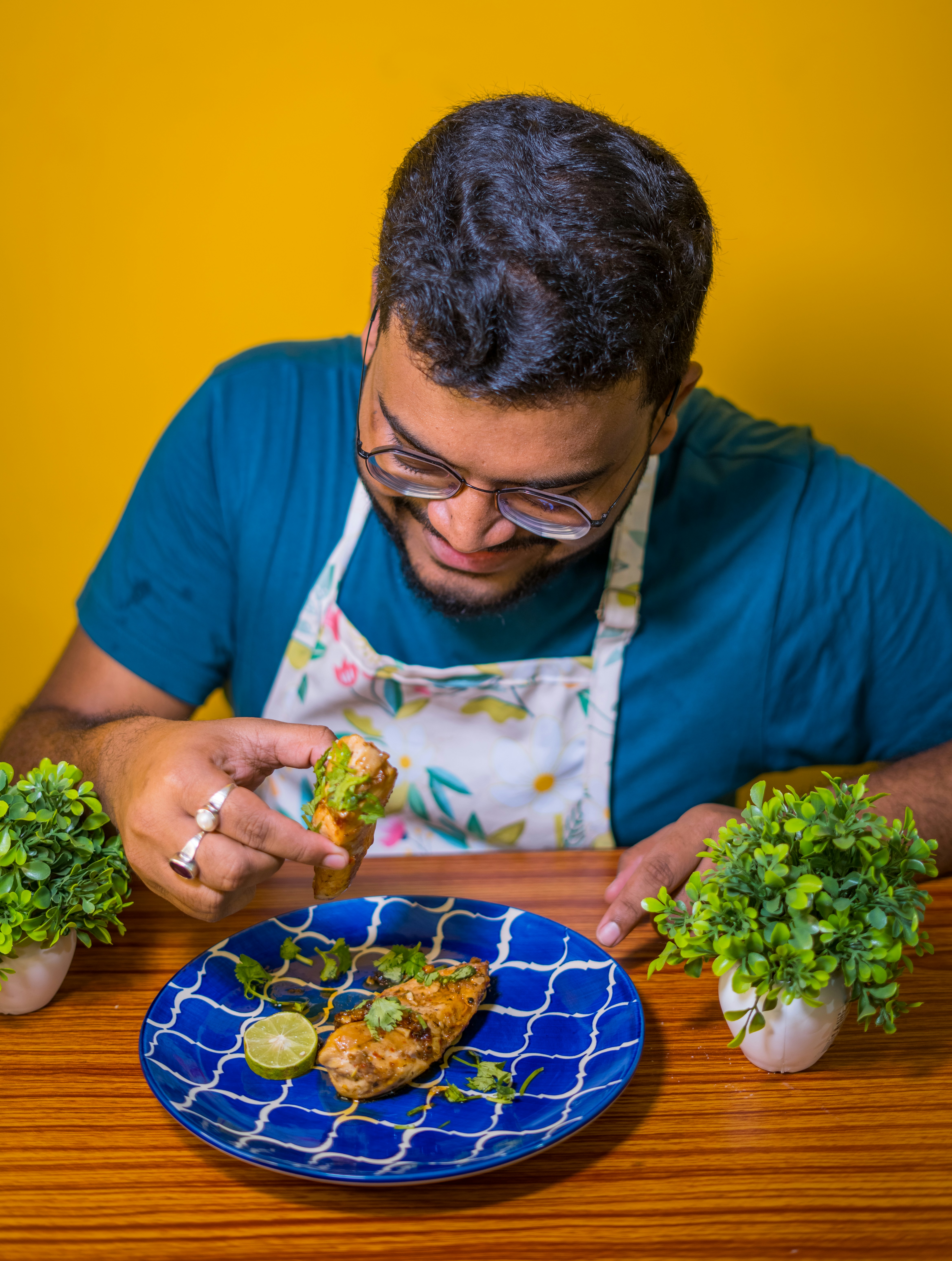 Focused Bite: A chef in teal trims a bite of herb-tushed chicken at a sunny dinner table