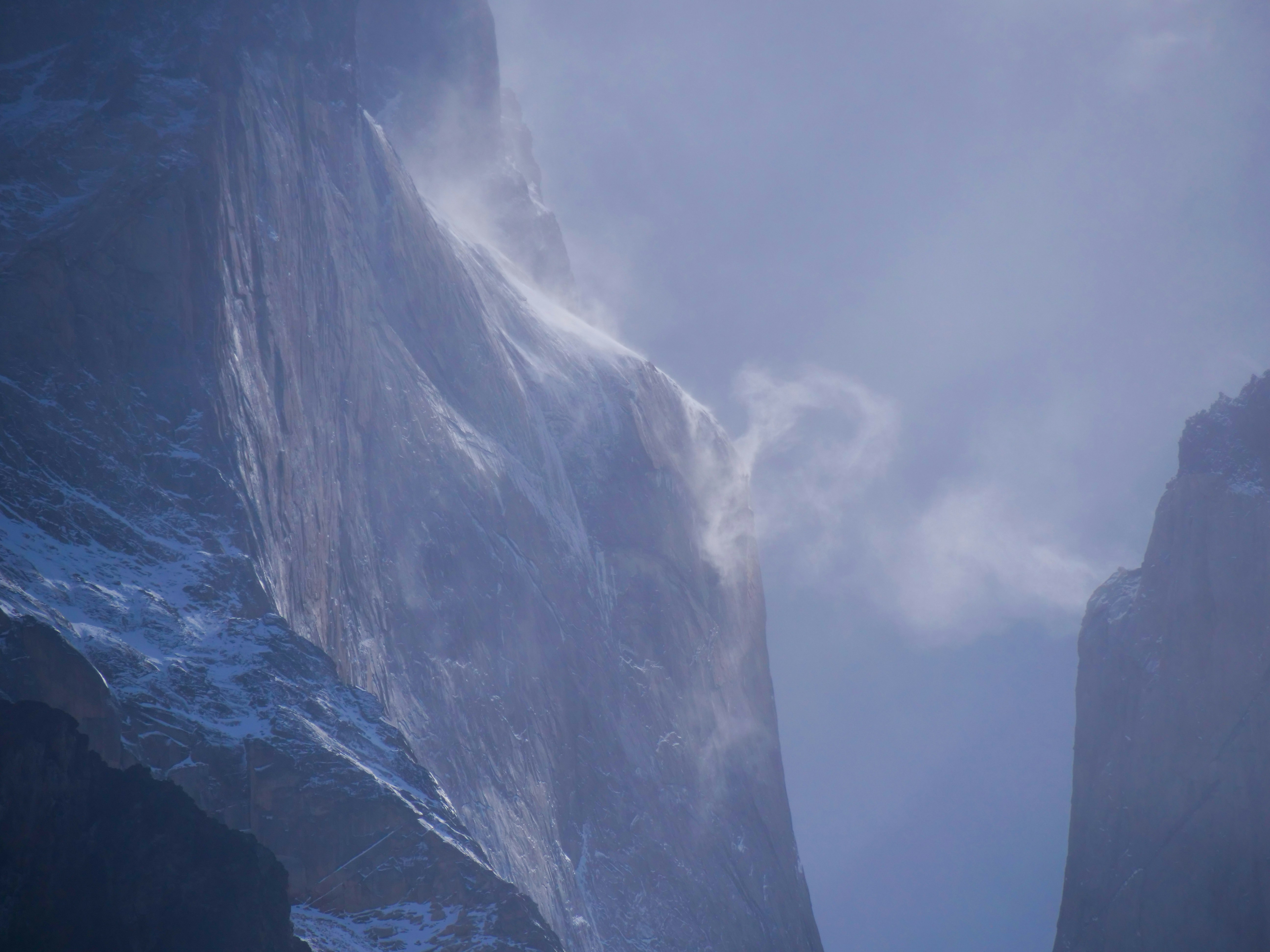 Snow-dusted cliffs with mist swirling between towering rock formations.