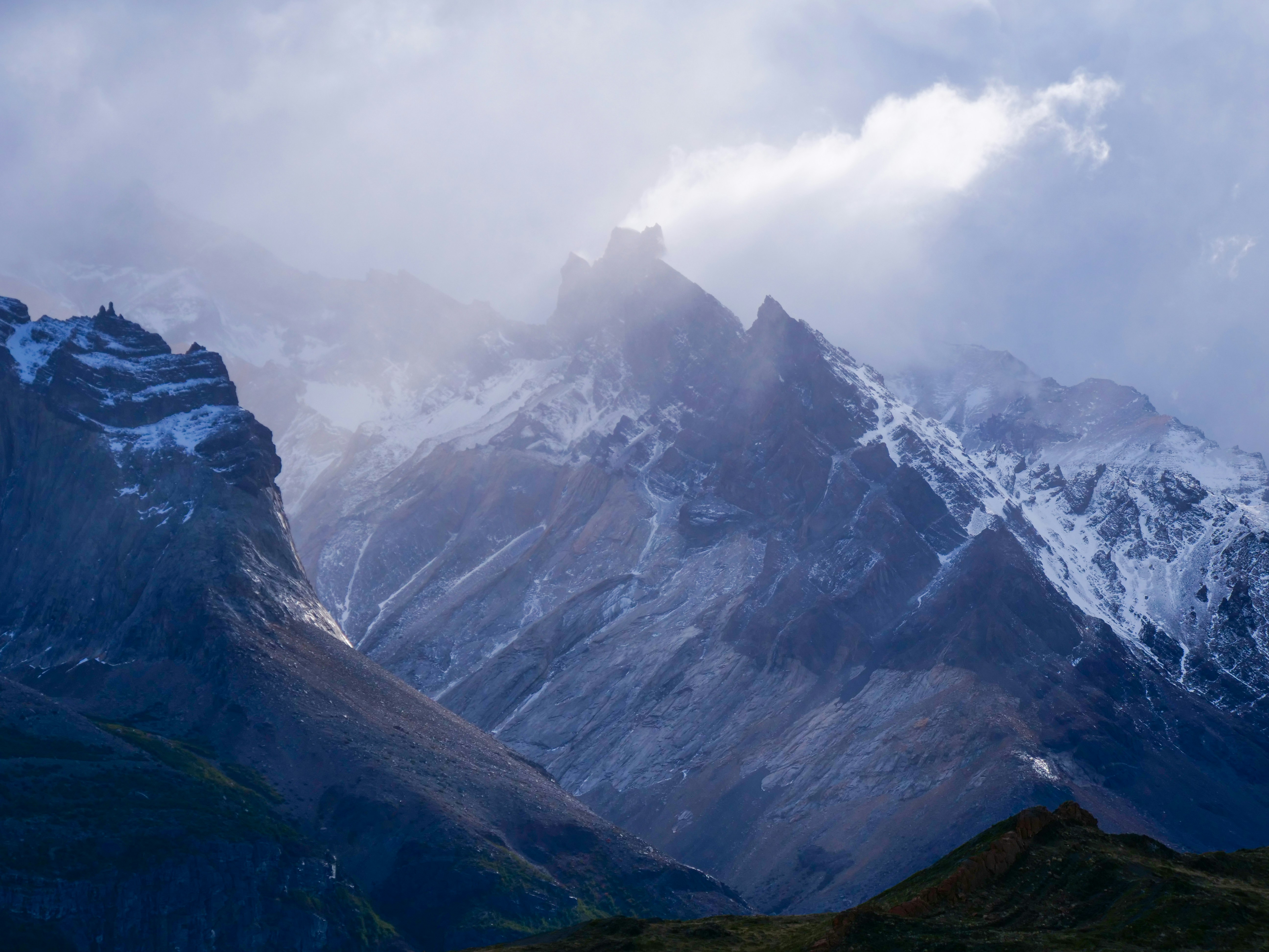 Sunlight pierces through clouds, illuminating snow-dusted mountain peaks.