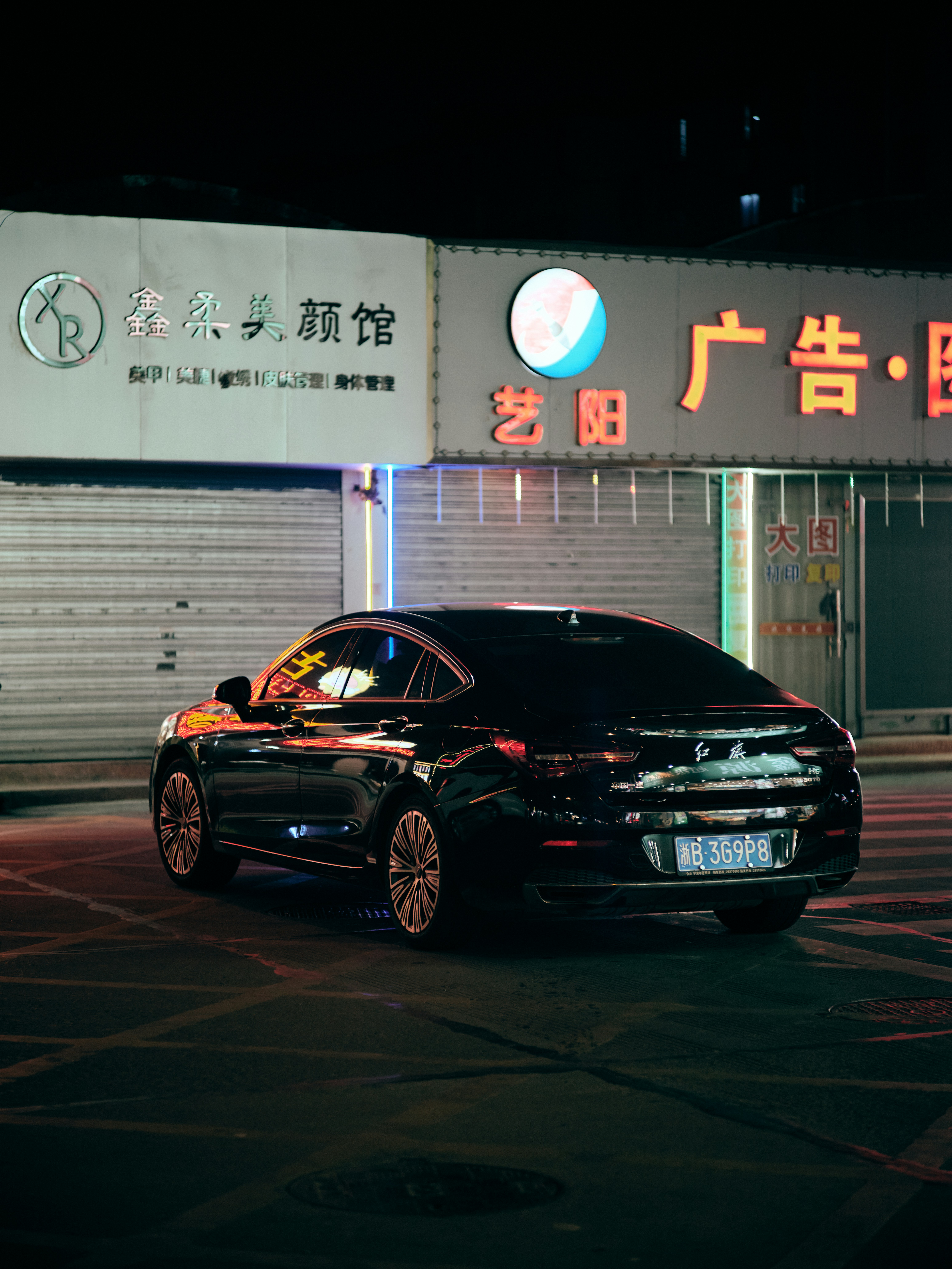 Midnight Alloy: A black sedan framed by neon storefronts