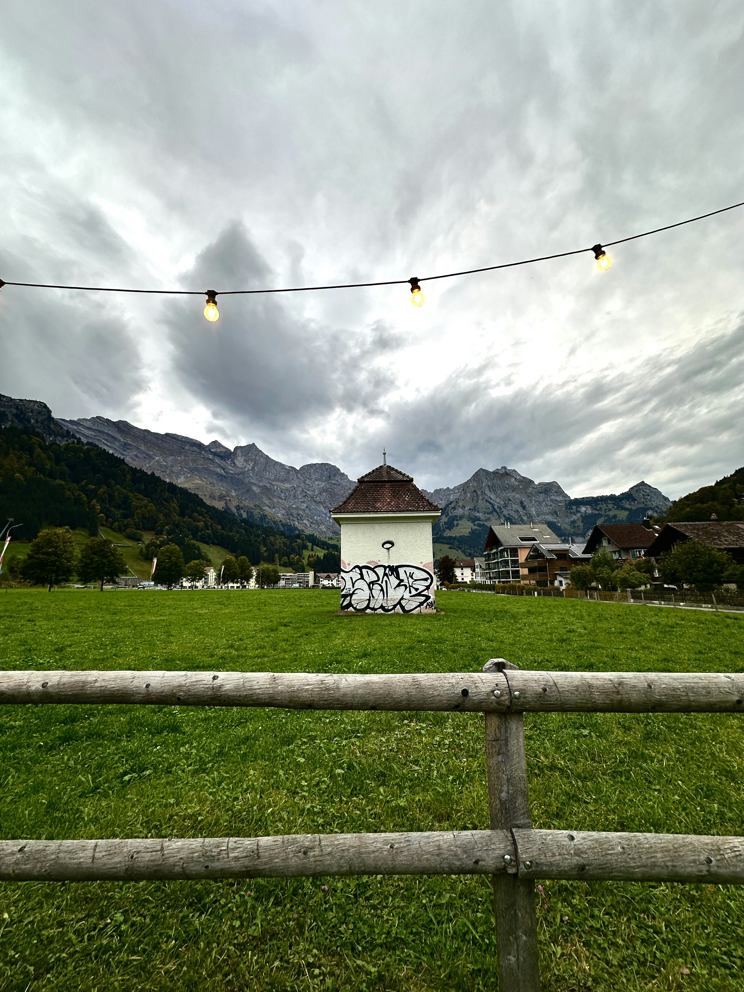 String lights over a rustic scene by the alpine field