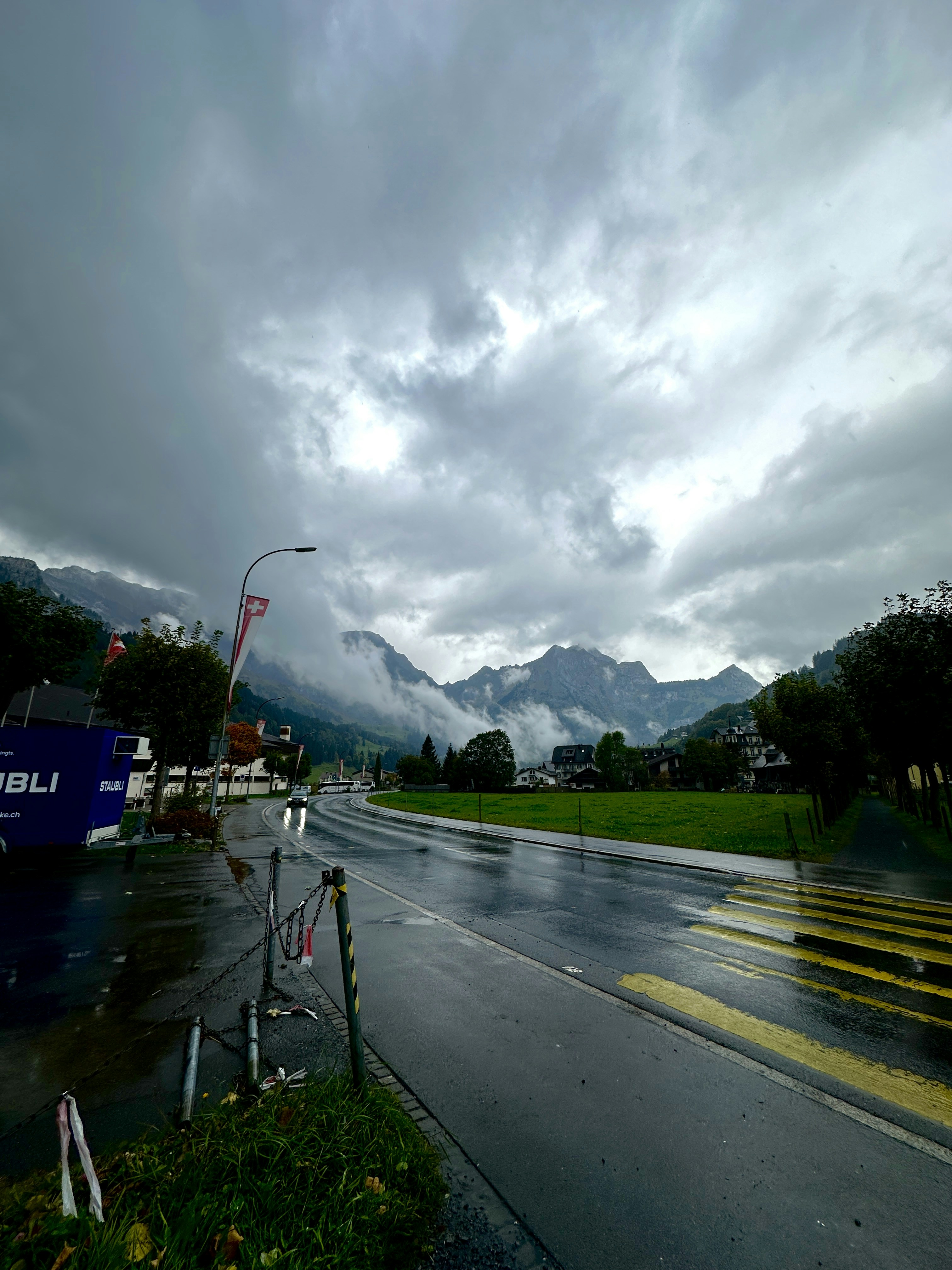 Rain-Washed Valley Road Under Cloud-Crowned Peaks