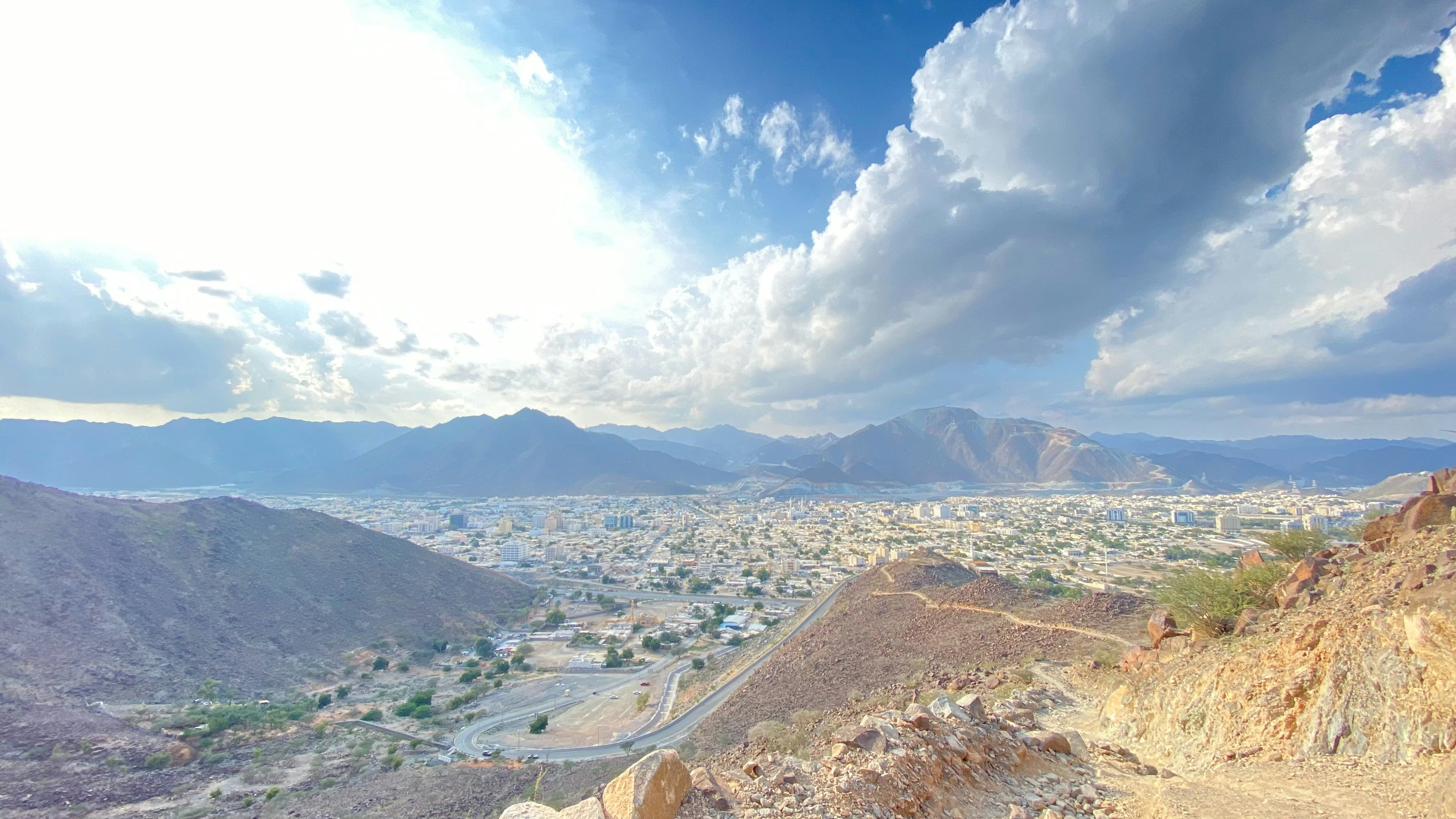 Expansive mountain range under a dynamic sky with sunlight illuminating the valleys.