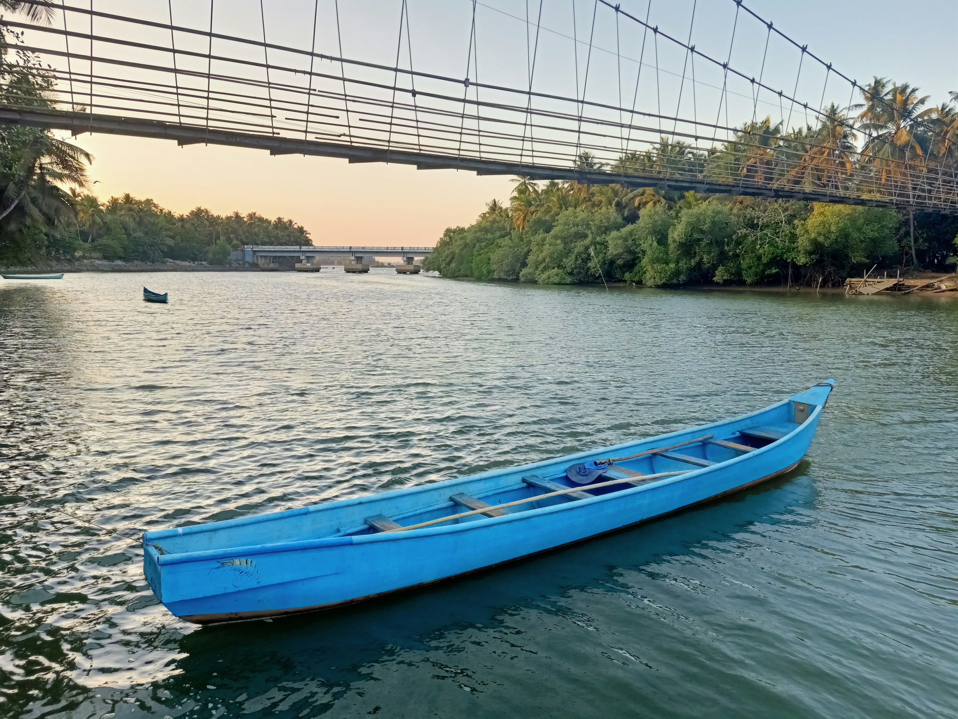 A blue boat floating on top of a river under a bridge photo – Free ...