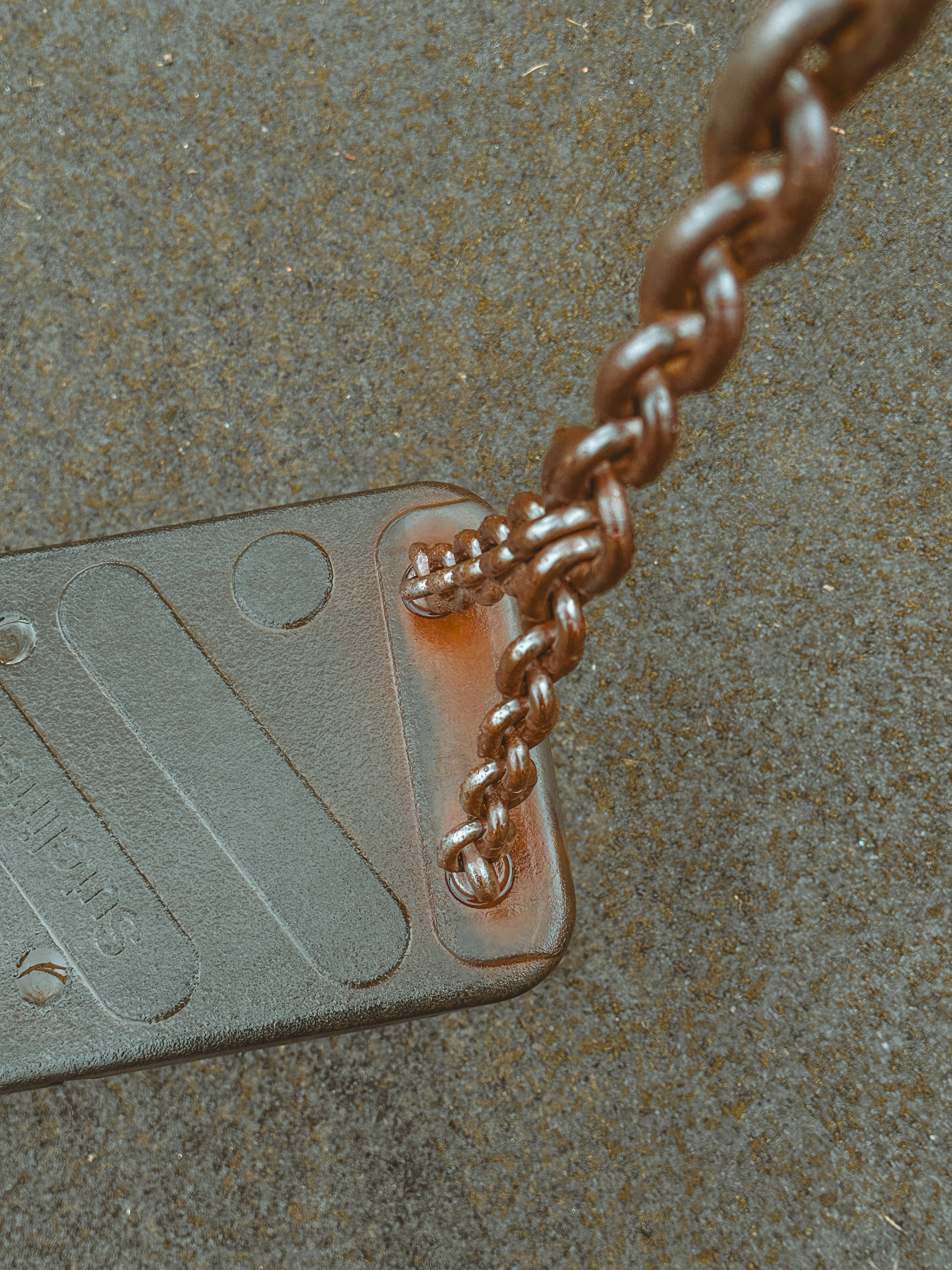 Rust and Routine: macro close-up of a chain anchored to a weathered plate