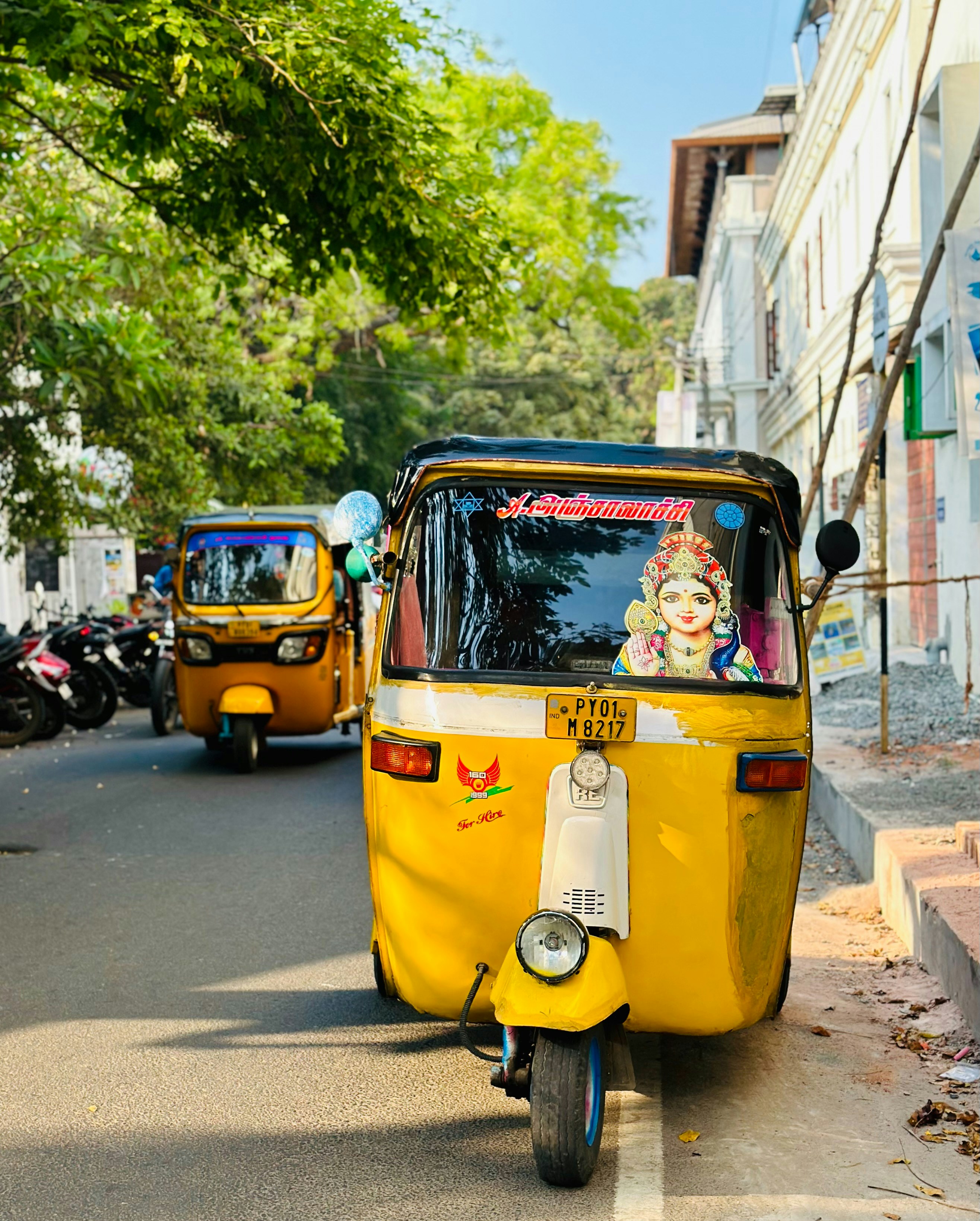 A yellow tuk tuk driving down a street photo – Free Wheel Image on Unsplash