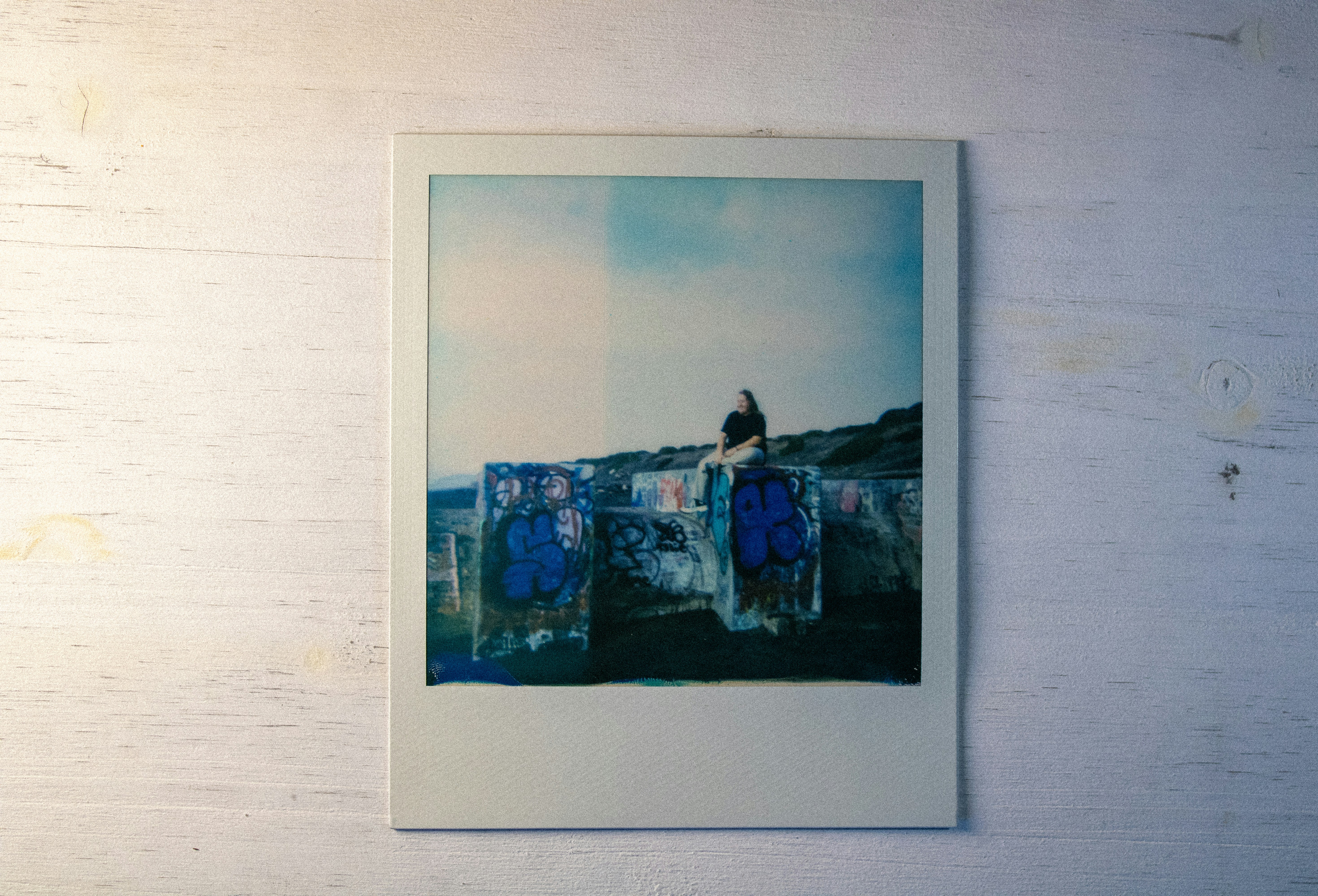 Polaroid Pause: A Figure Among Graffiti by the Sea