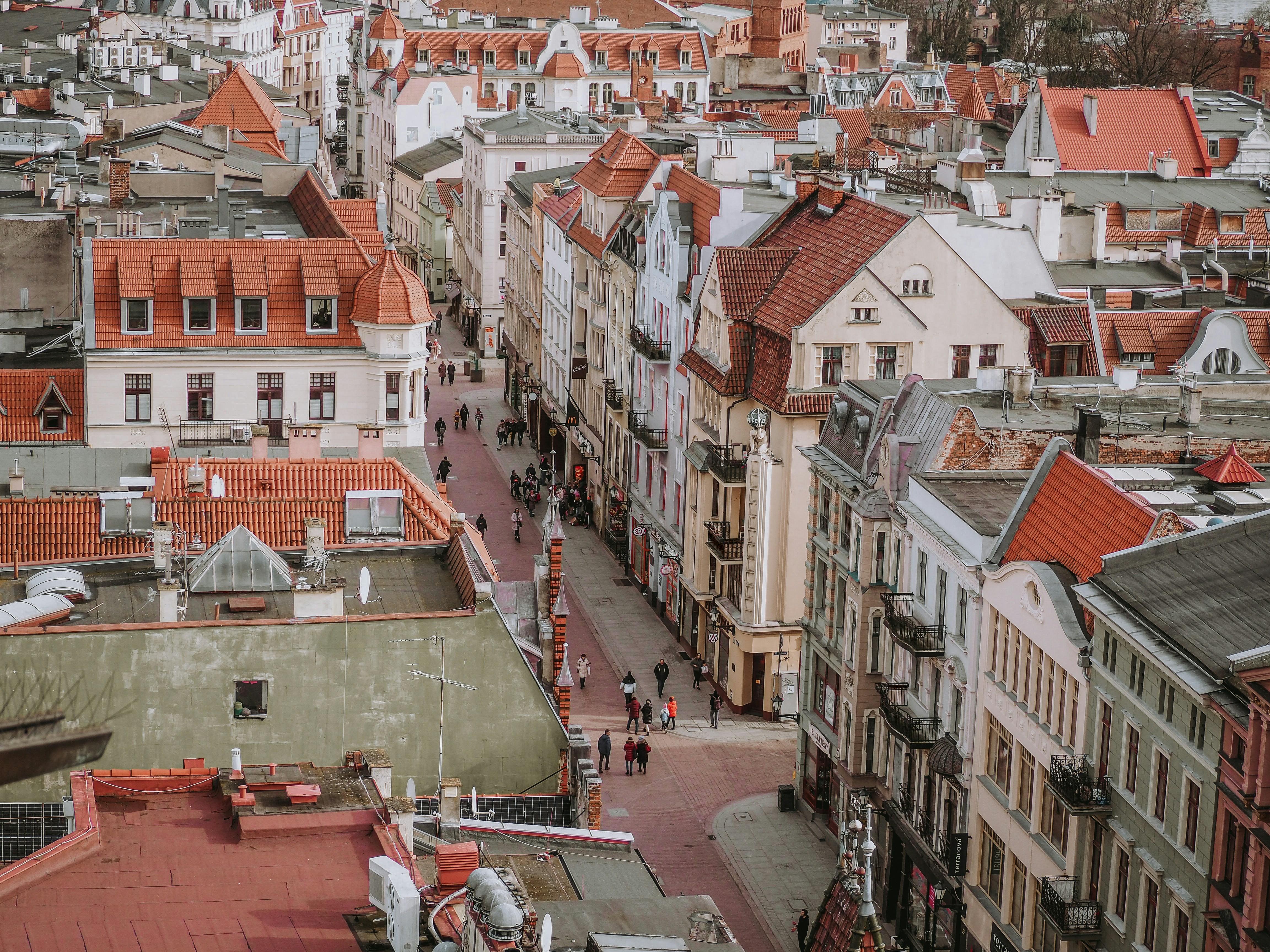 Aerial view of a quaint European street lined with historic buildings and red-tiled roofs.