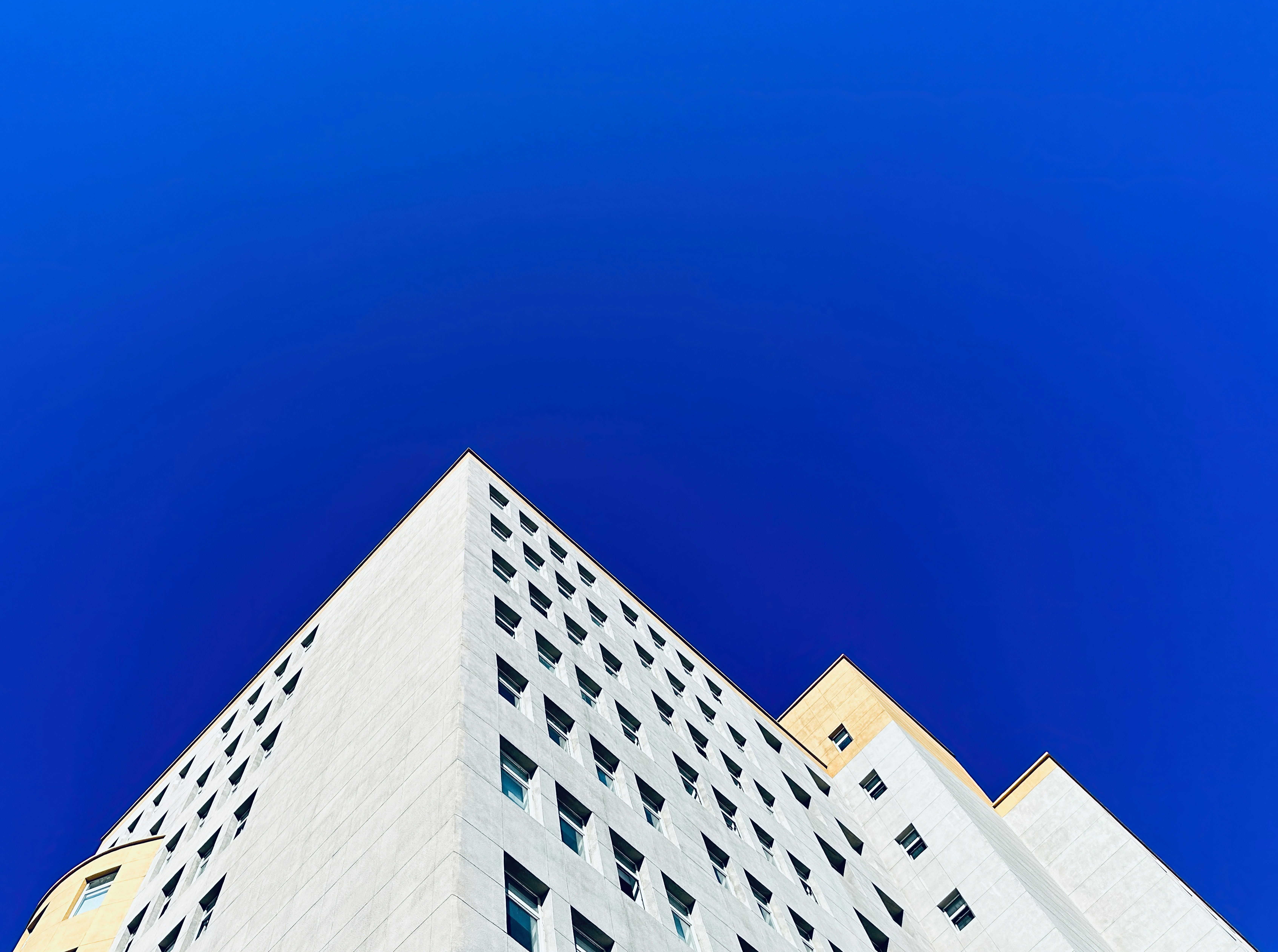 Modern building facade with geometric windows under a deep blue sky.