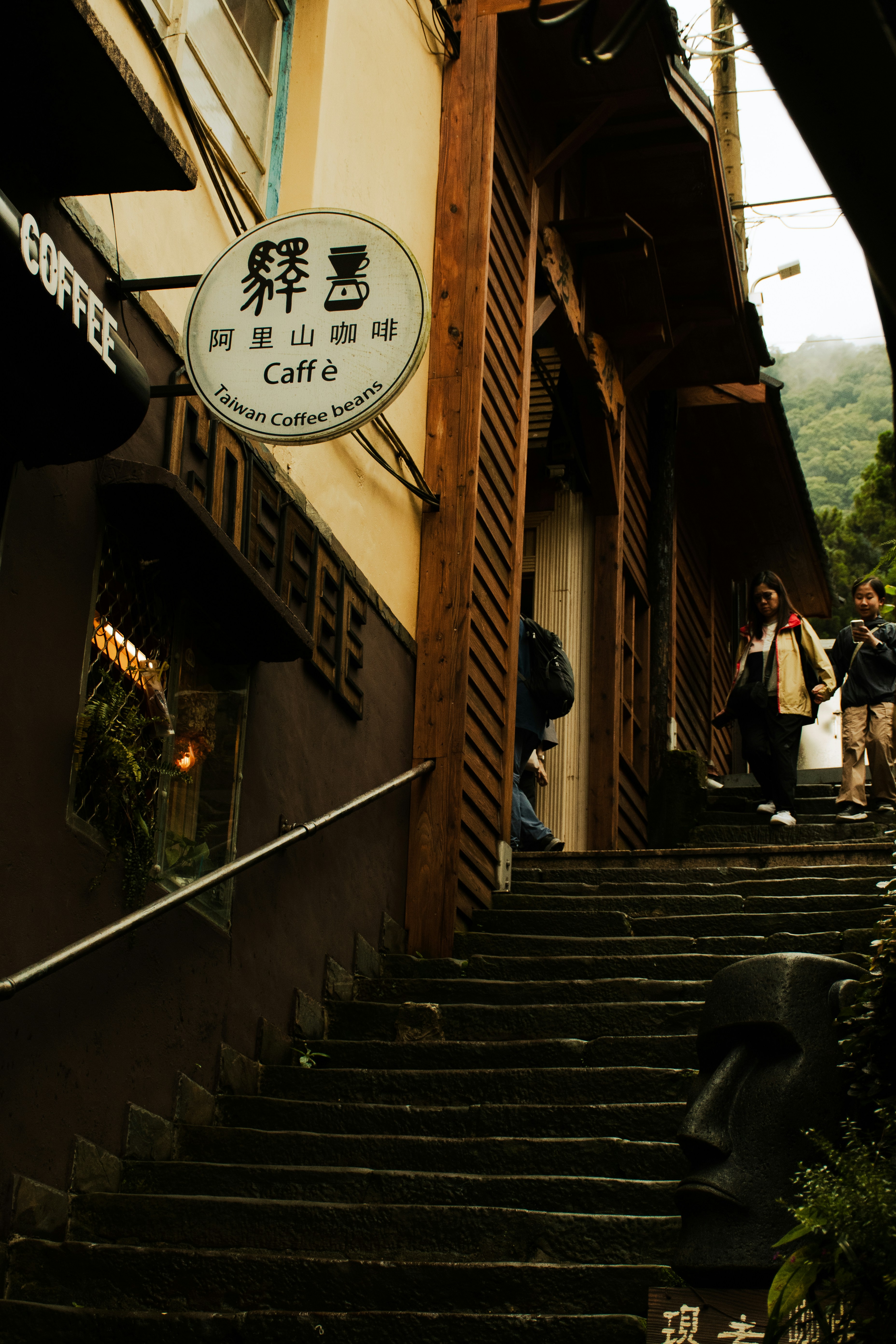 Circular Taiwan Coffee Sign Framing a Narrow Wooden Staircase