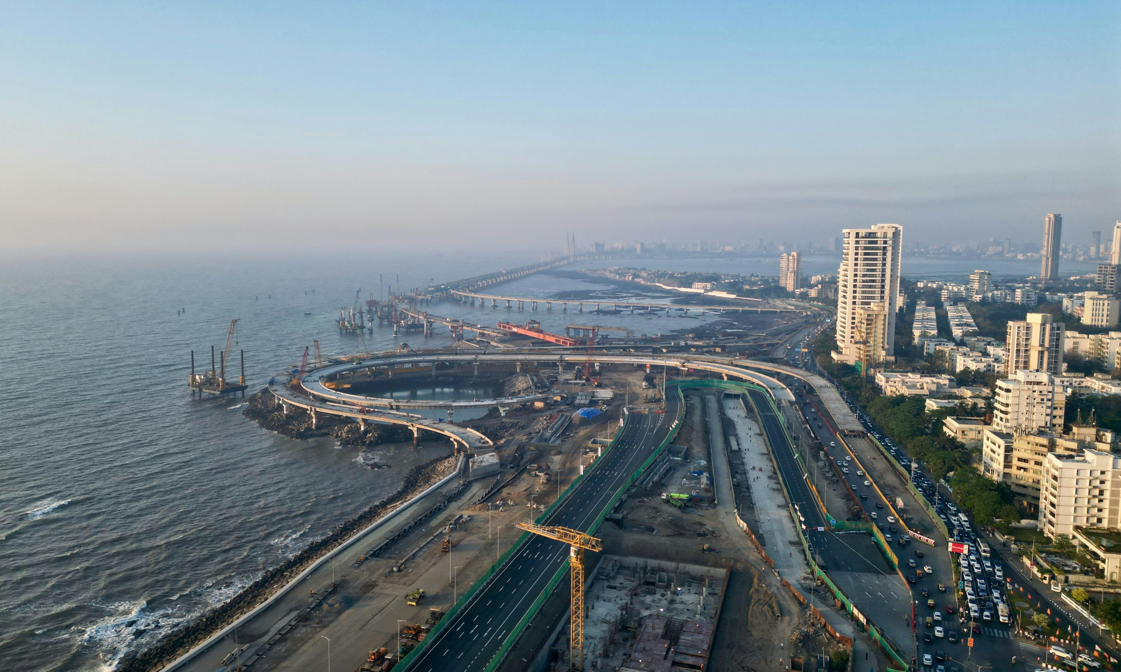 A view of the new Mumbai Coastal Road at Worli Sea Face with the Bandra Worli Sea Link in Distance. The Mumbai Coastal Road, officially named as Dharmveer Swarajya Rakshak Chhatrapati Sambhaji Maharaj Coastal Road is a partially opened 8-lane, 29.2-km long grade separated expressway along Mumbai's western coastline connecting Marine Lines in the south to Kandivali in the north.