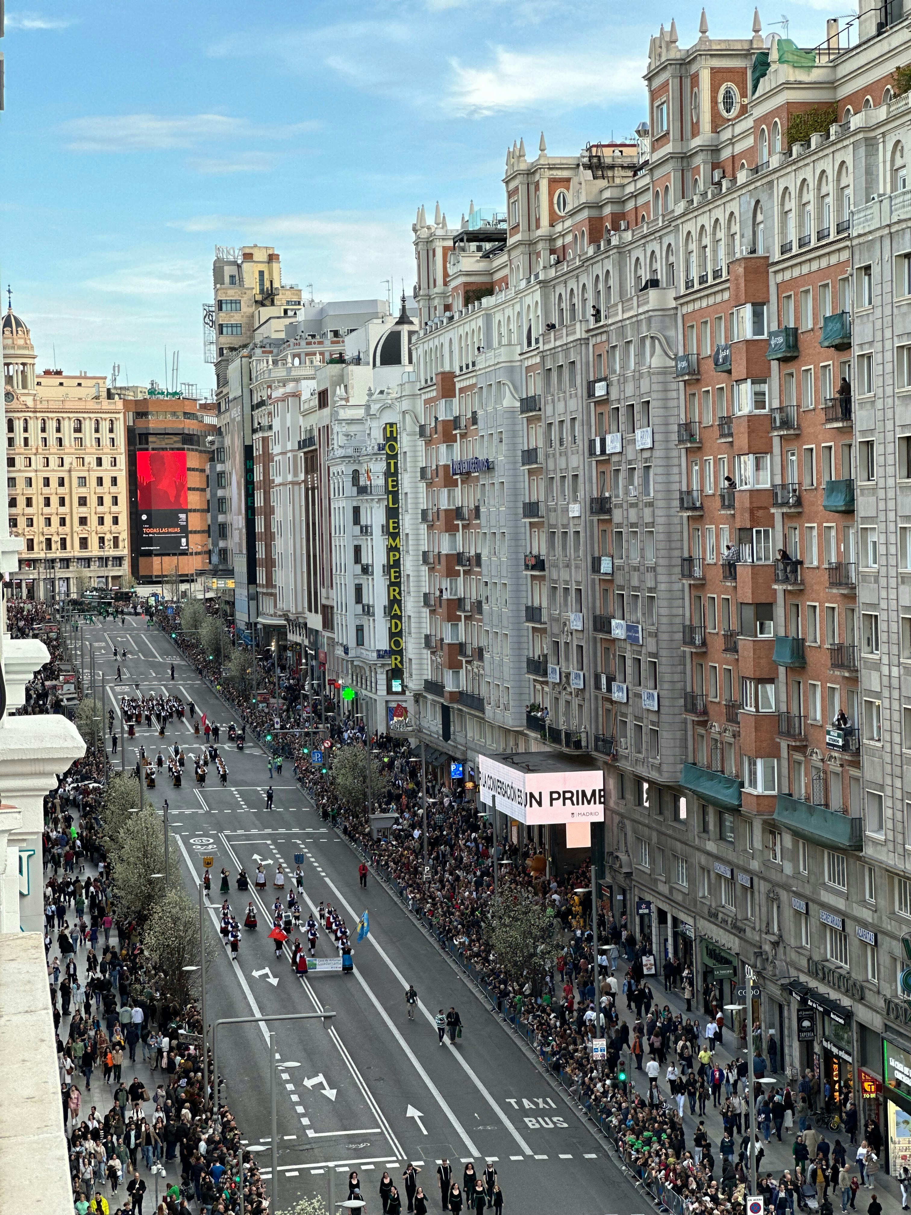 Crowd-Threaded Boulevard: An Aerial Parade Over a Bustling City Street