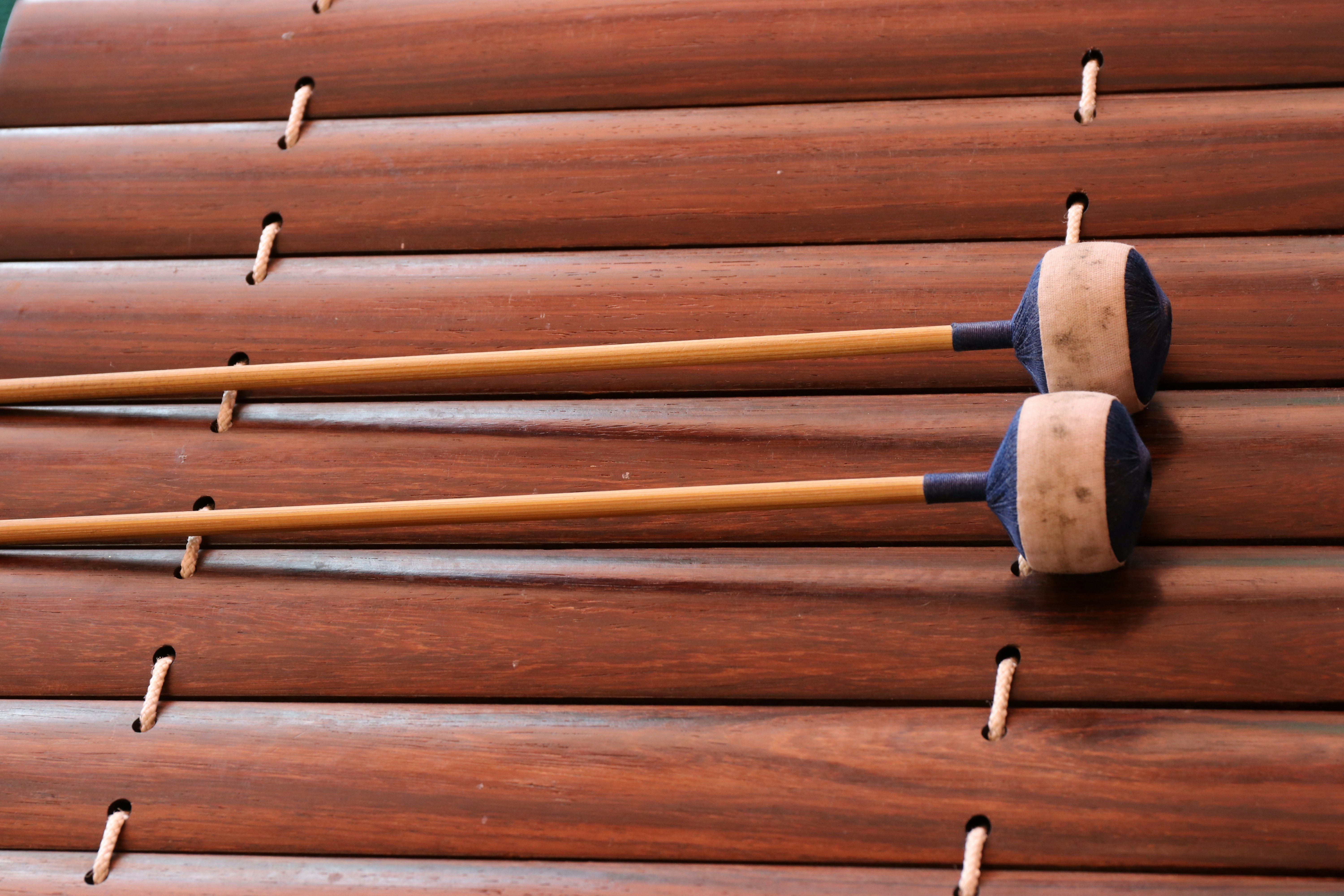 Wooden xylophone bars with two mallets resting on top, set in a serene outdoor environment.