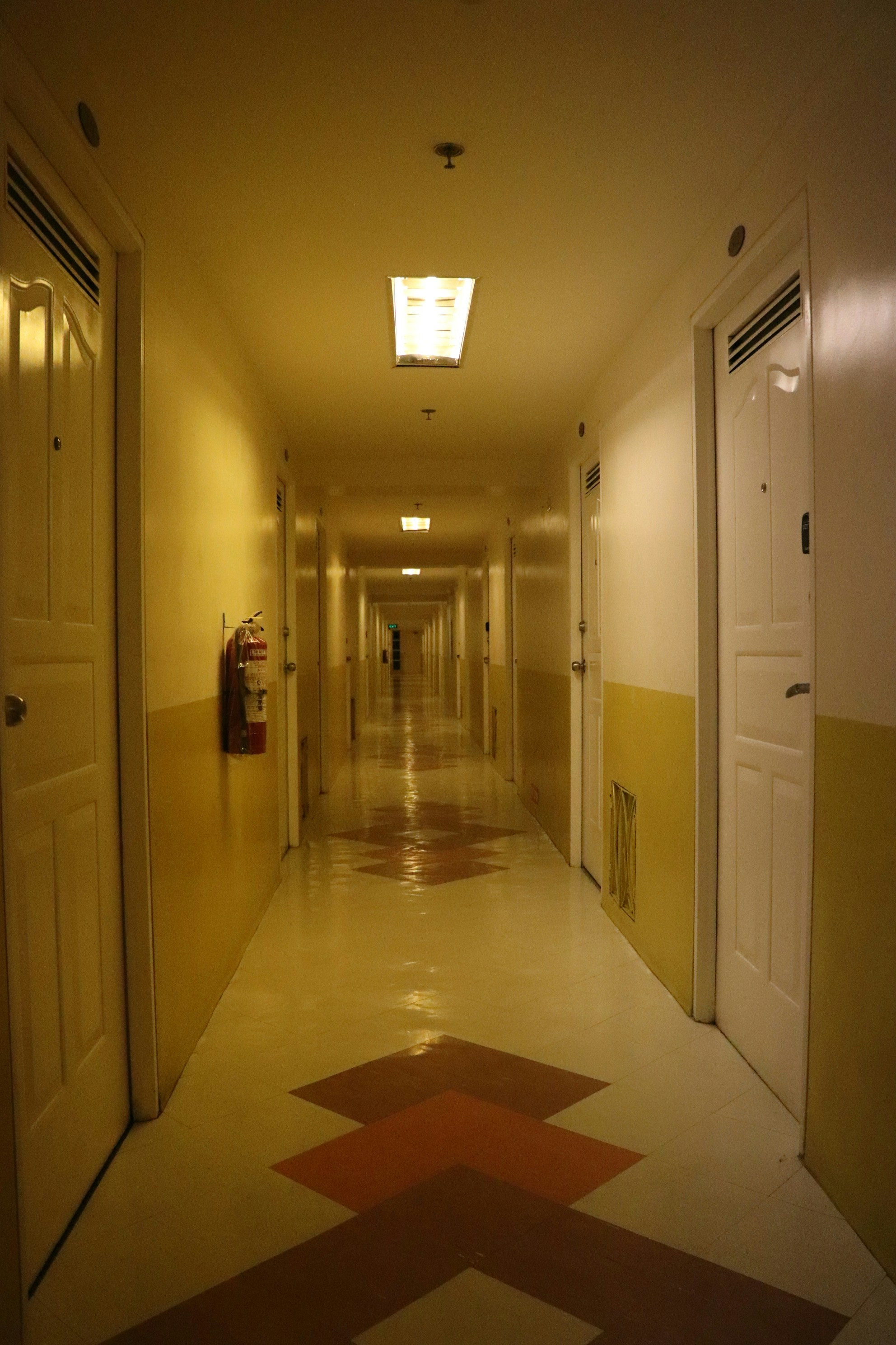A long hallway with yellow walls and red and white flooring photo ...