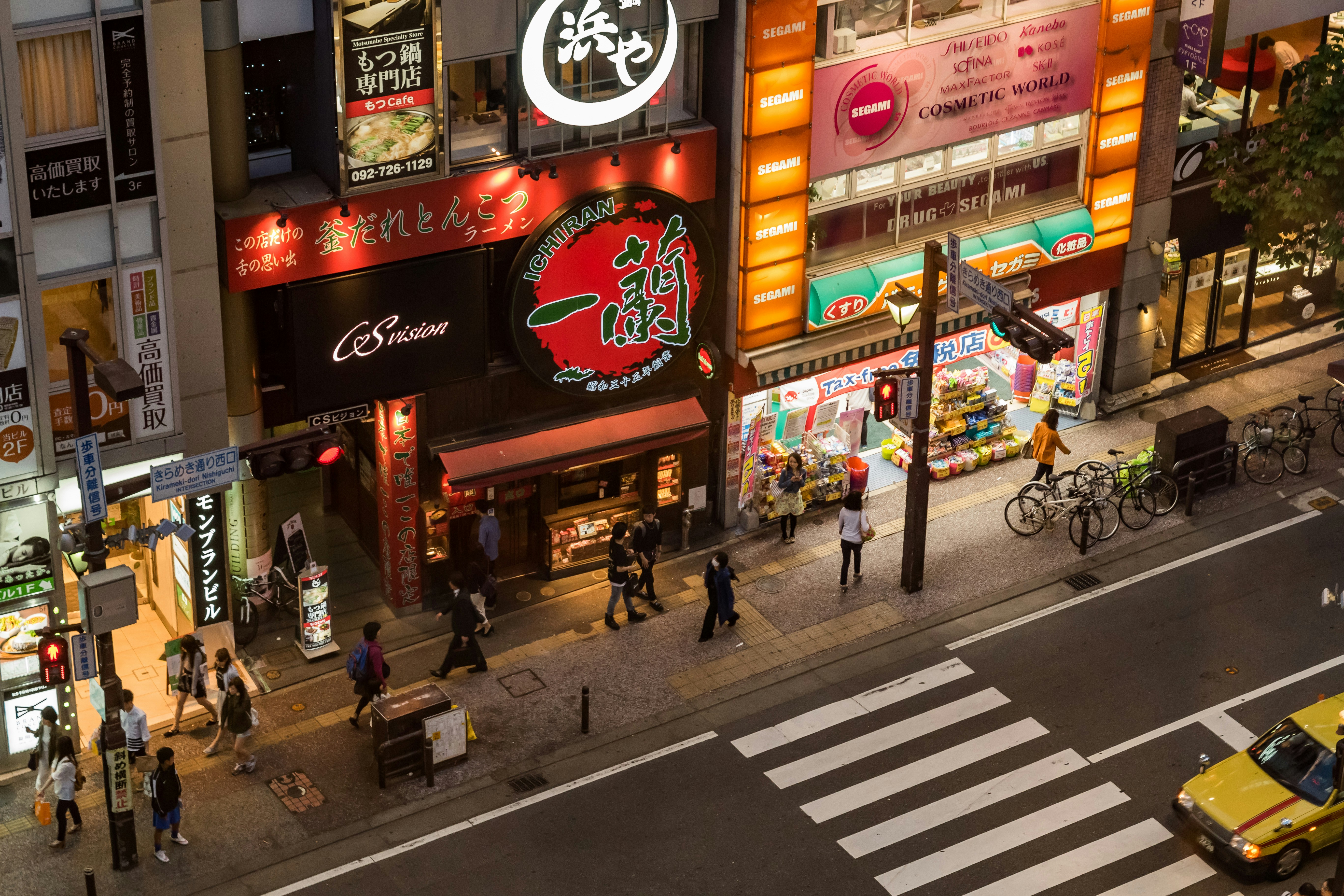 Vibrant street scene in a bustling city, showcasing shops and pedestrians under neon lights. The focus is on a restaurant with a striking red sign.